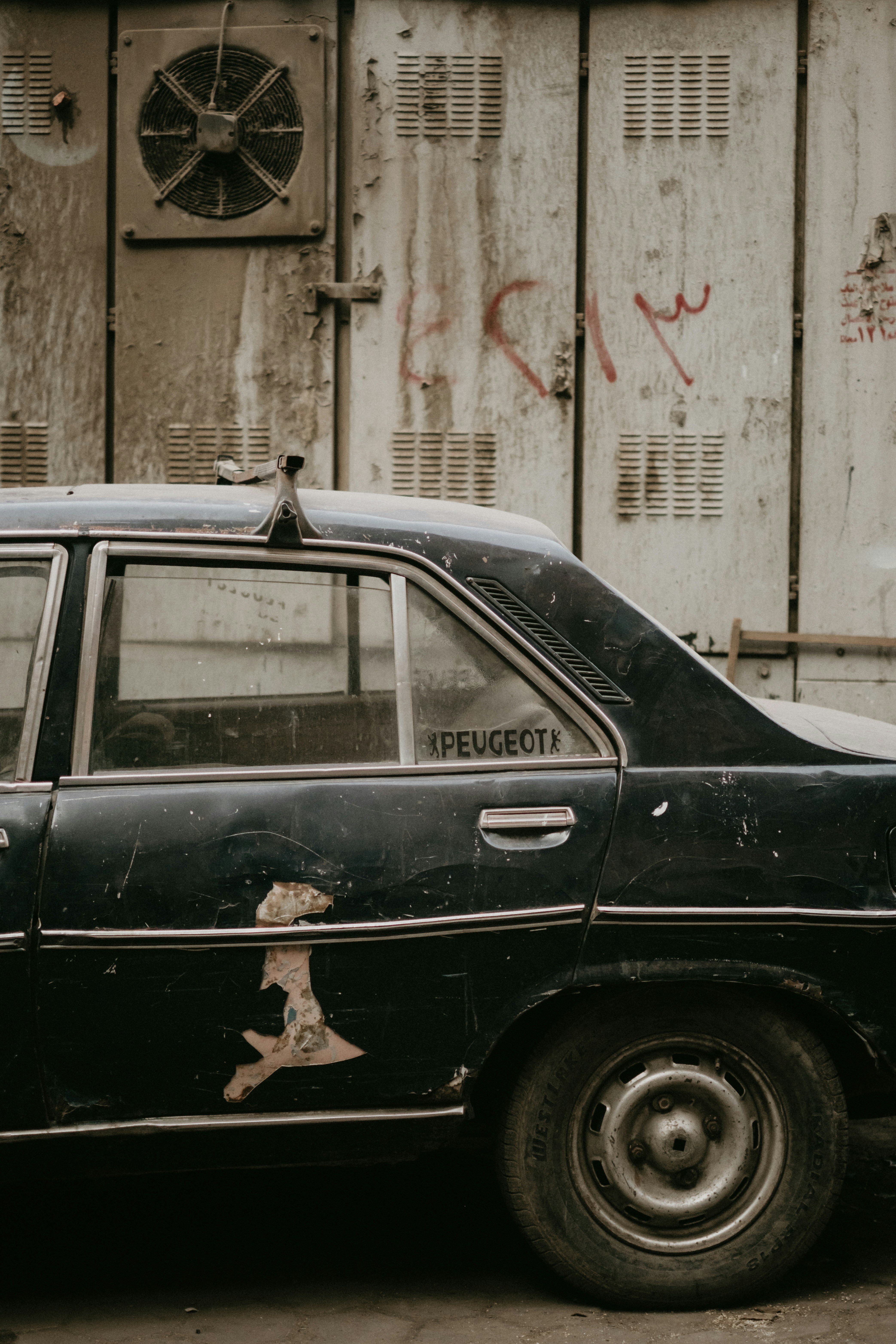Rusted Peugeot, Still Standing by a Weathered Wall