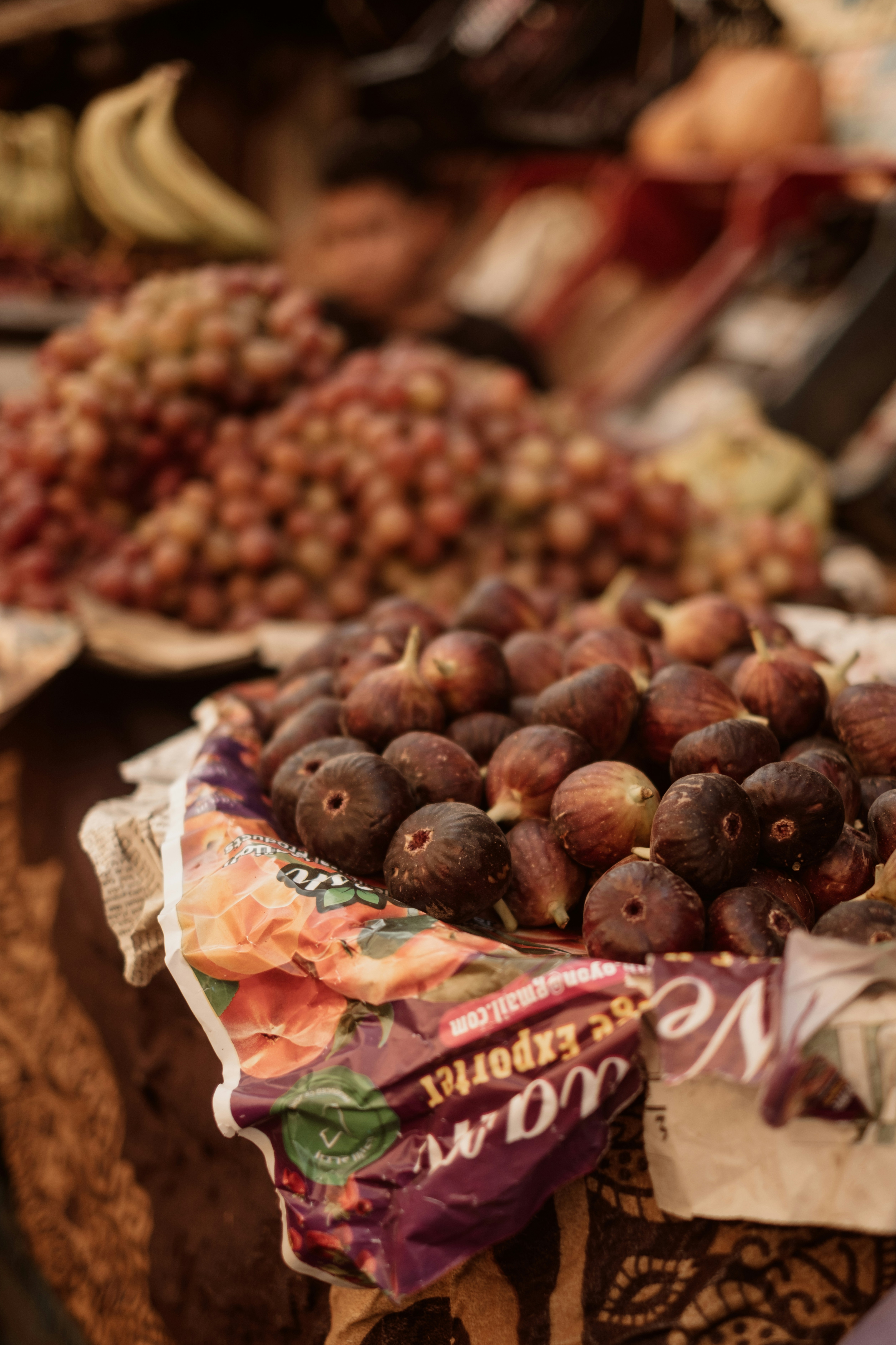 Grapes and Figs spill over a colorful market display wrapped in crinkled newspaper