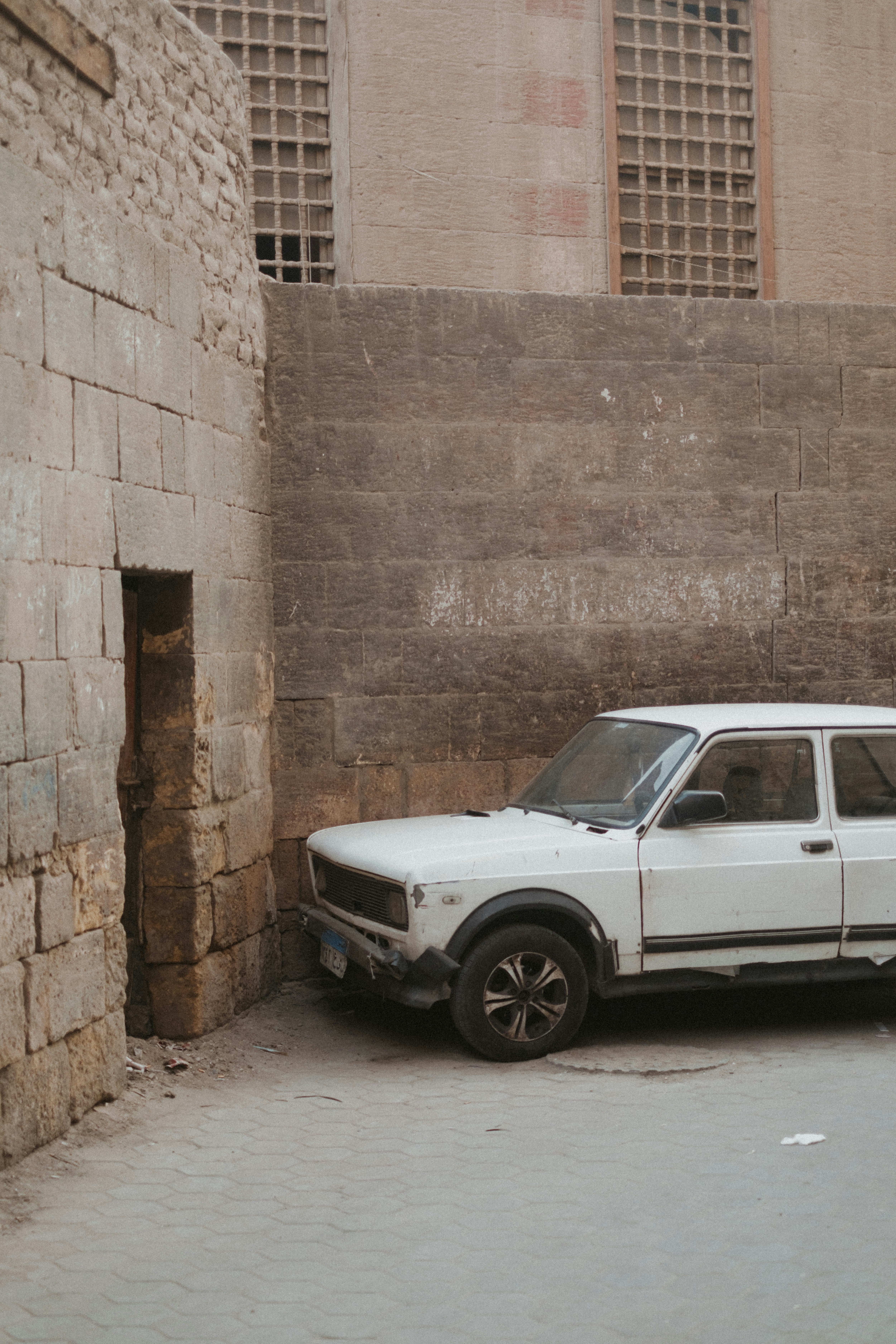 A Weathered Classic: White Sedan Resting Against Deserted Walls