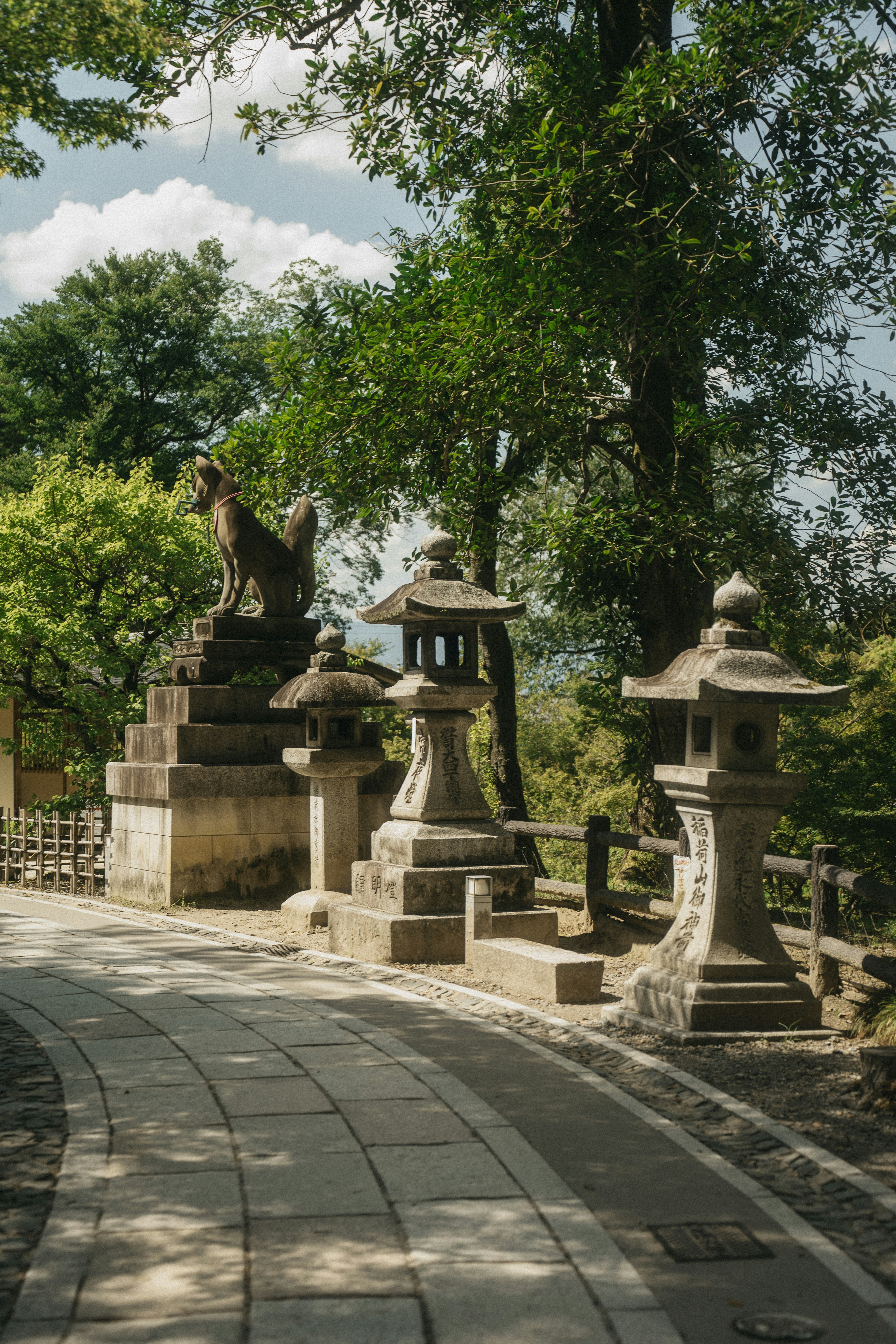 Stone Lanterns and Guardian Statues Along a Shaded Temple Path