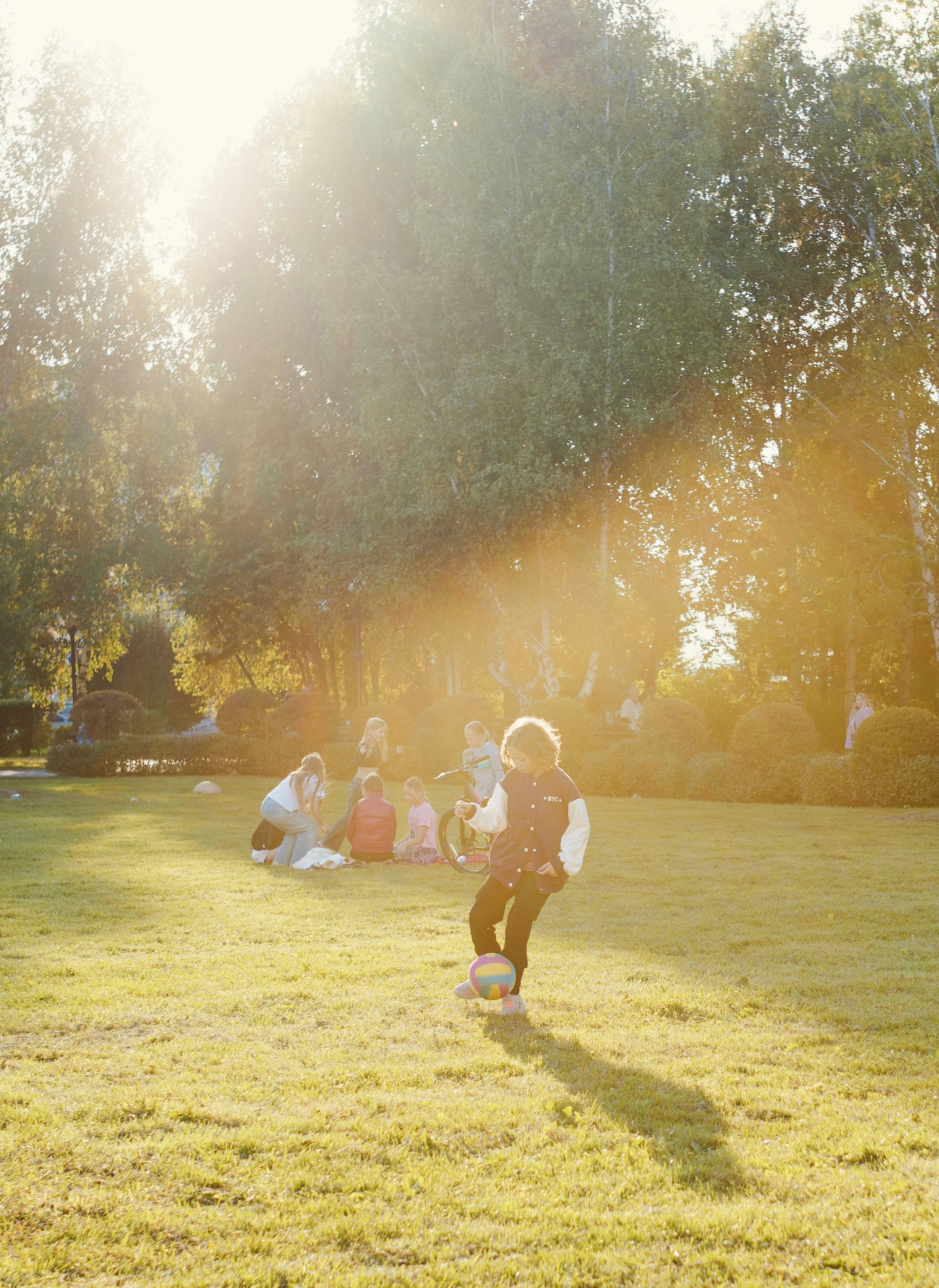Sunlit Playground: A Child Champions a Ball in a Gilded Park