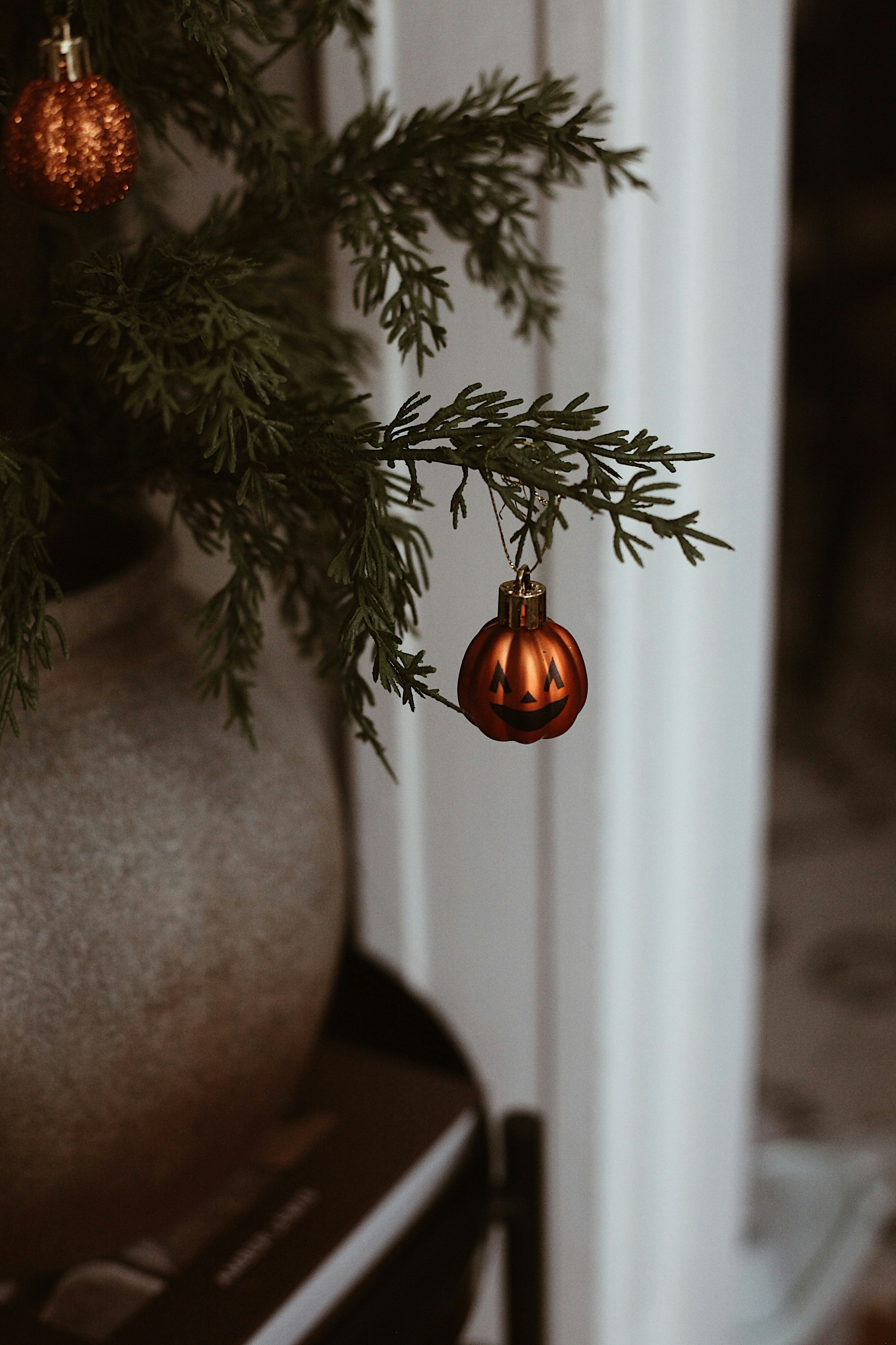 Pumpkin ornament on a pine branch in a softly lit indoor scene