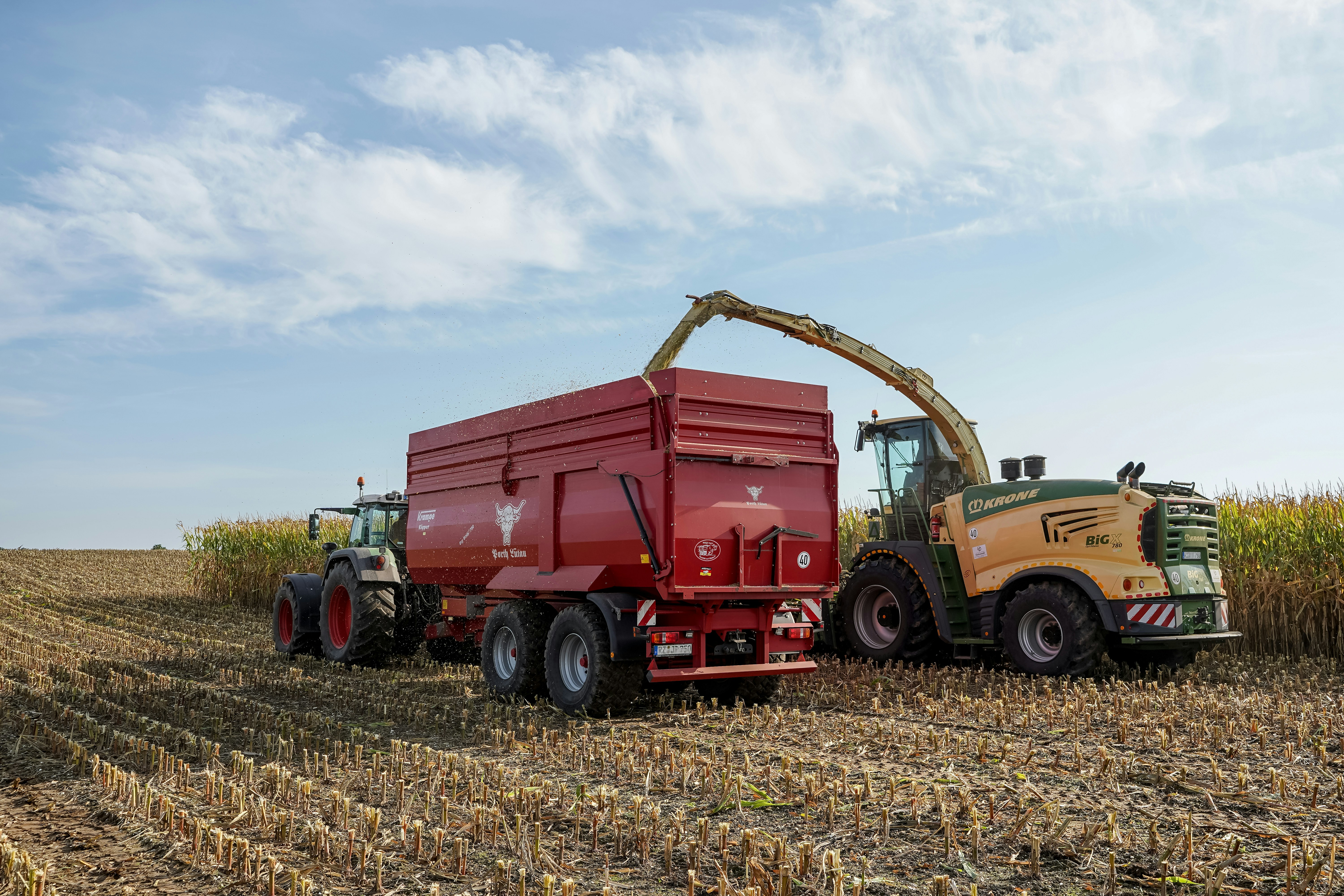 Waiting Harvest: Red trailer and yellow harvester meet in the field