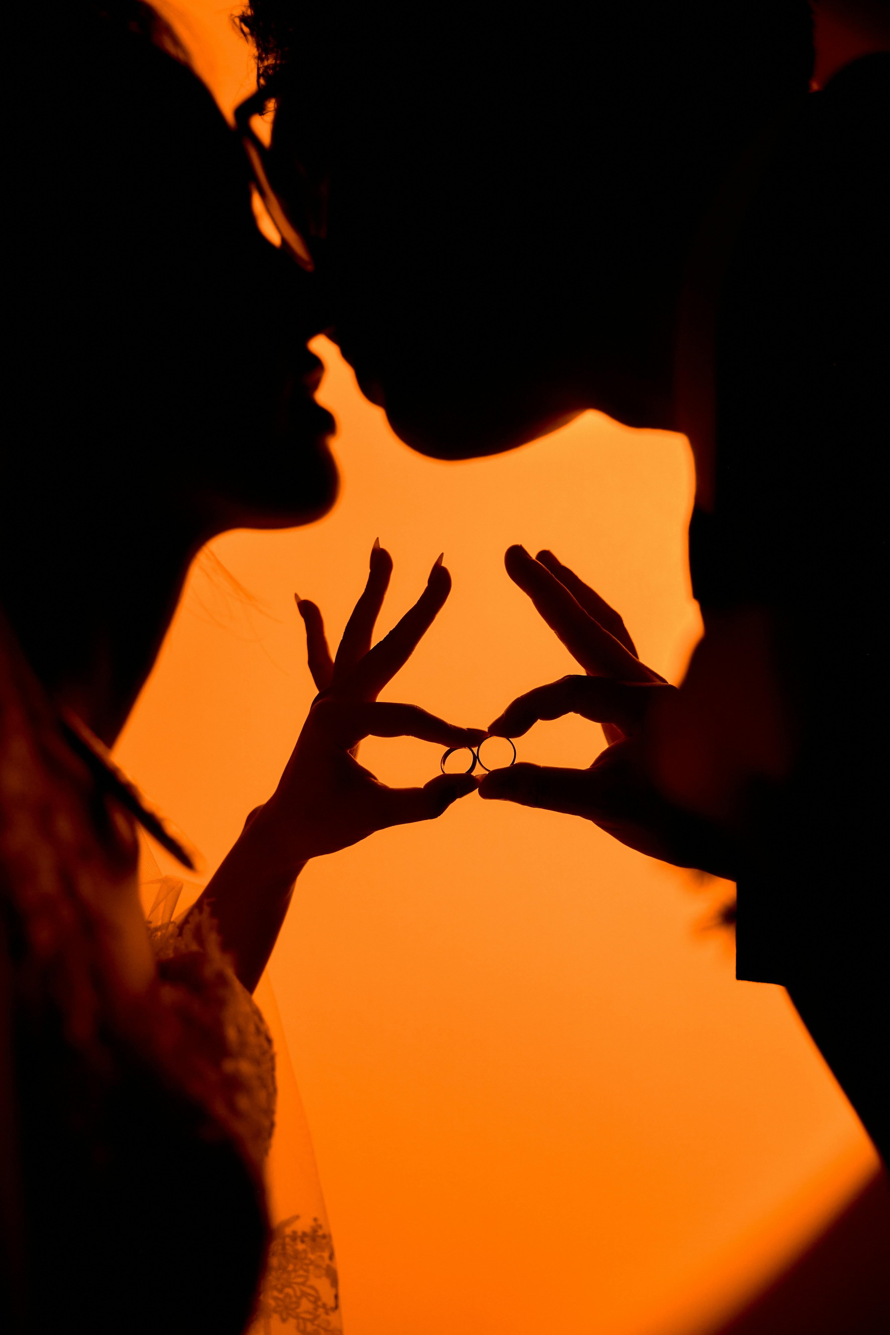Silhouettes in a Veiled Kiss: Wedding Ring Exchange Framed by Passion
