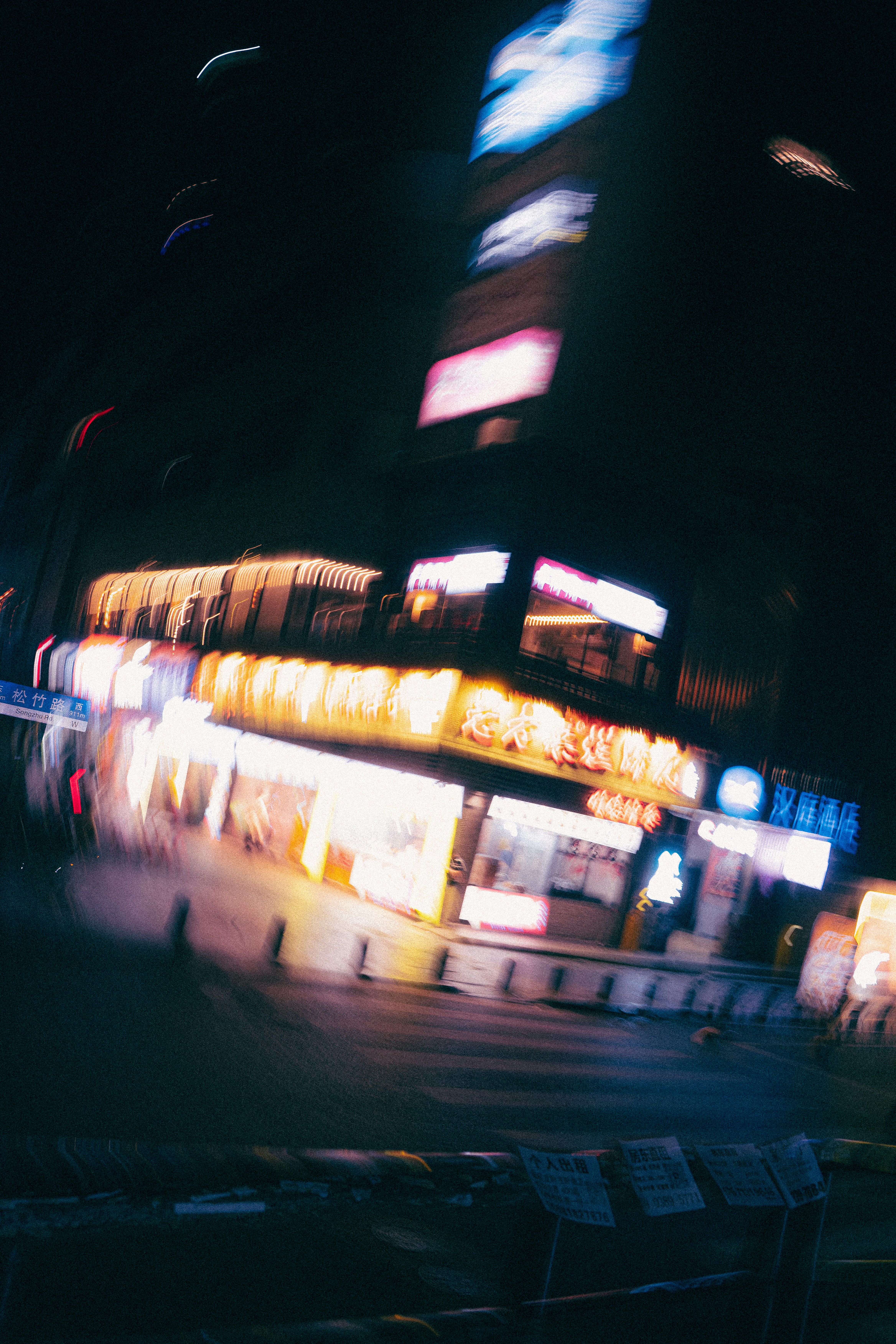 Blurred city storefronts and neon signs at night, captured with intentional camera motion to convey motion and energy; a storefront district with bright signage and pedestrians, likely a street scene. Illustration of urban nightlife.