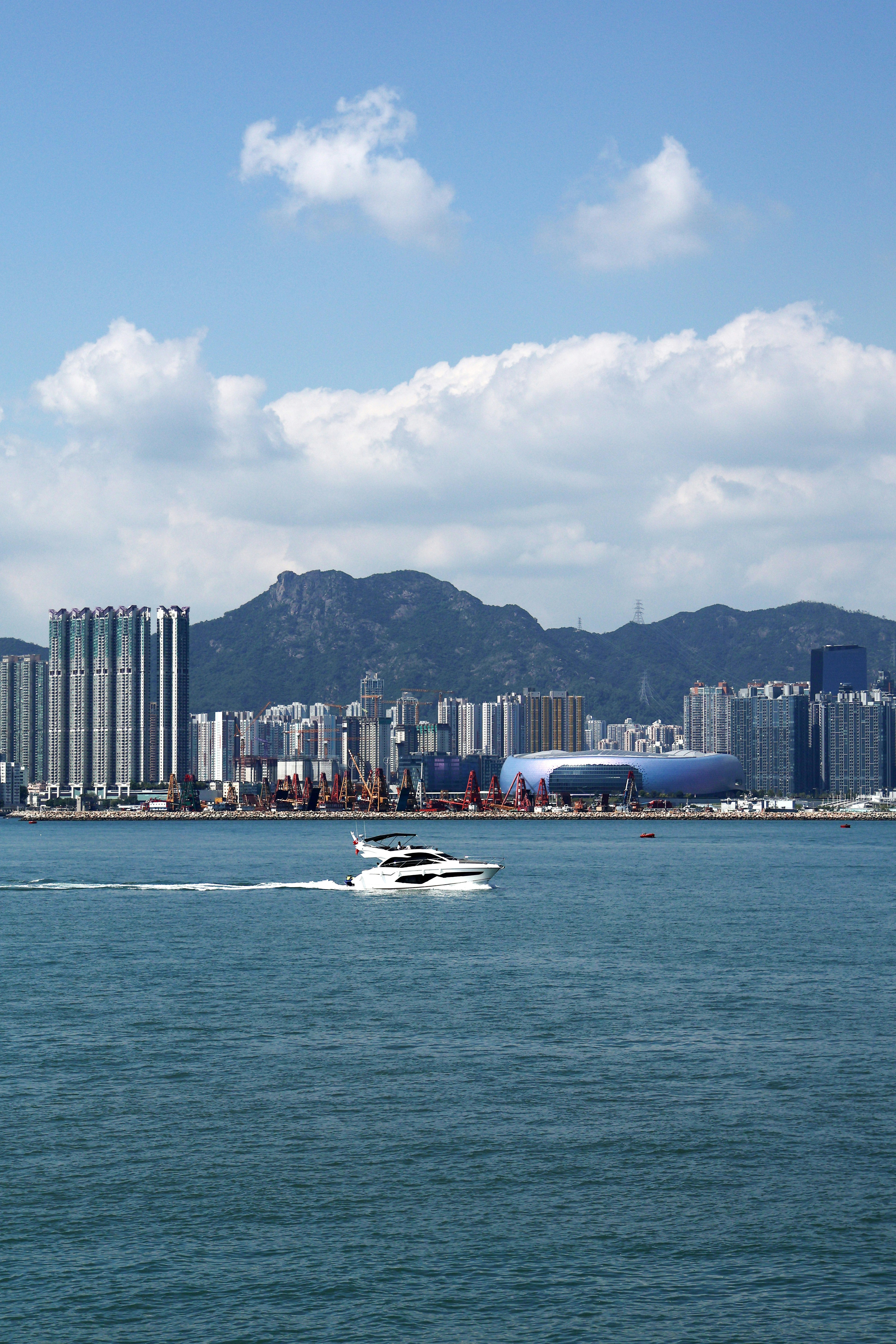 Cityscape on the horizon: speedboat carving a white wake