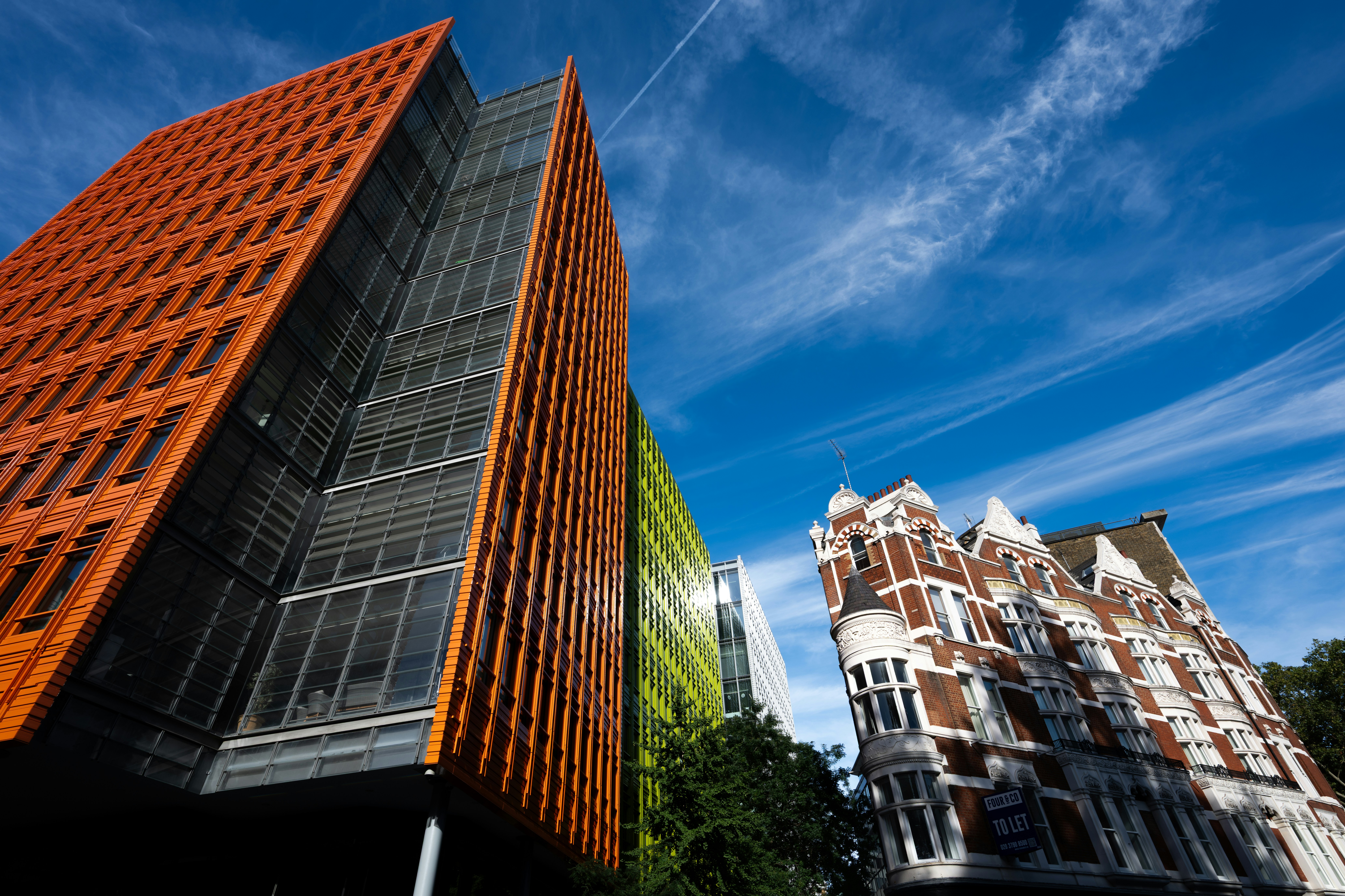 Chromatic Architecture: A Modern Orange Facade Meets Historic Corner
