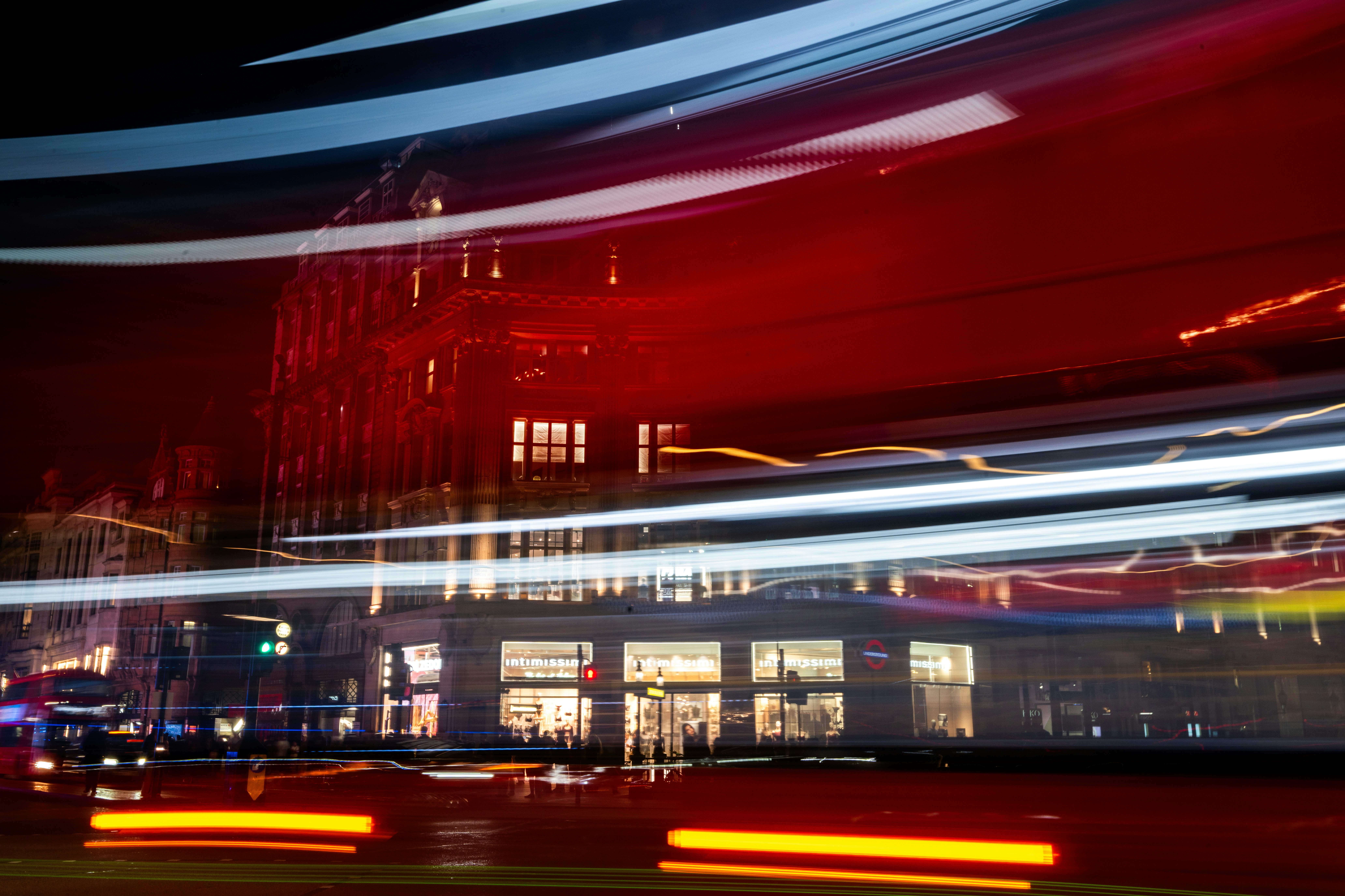 City Lights in Motion: A Streaked Nightlife Through Glass and Steel
