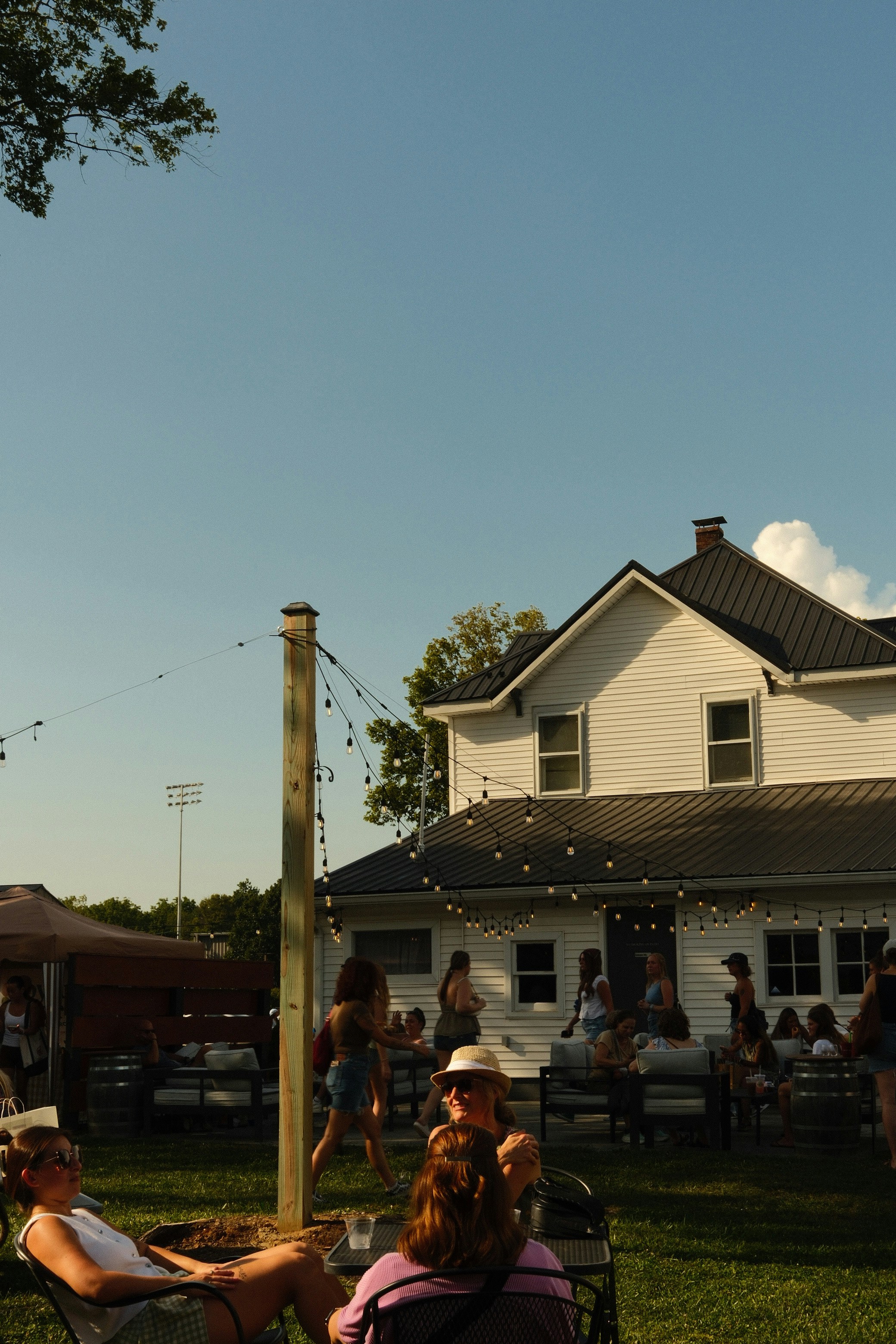 Sunlit Patio Social: Strings of Light Above a Cozy White House