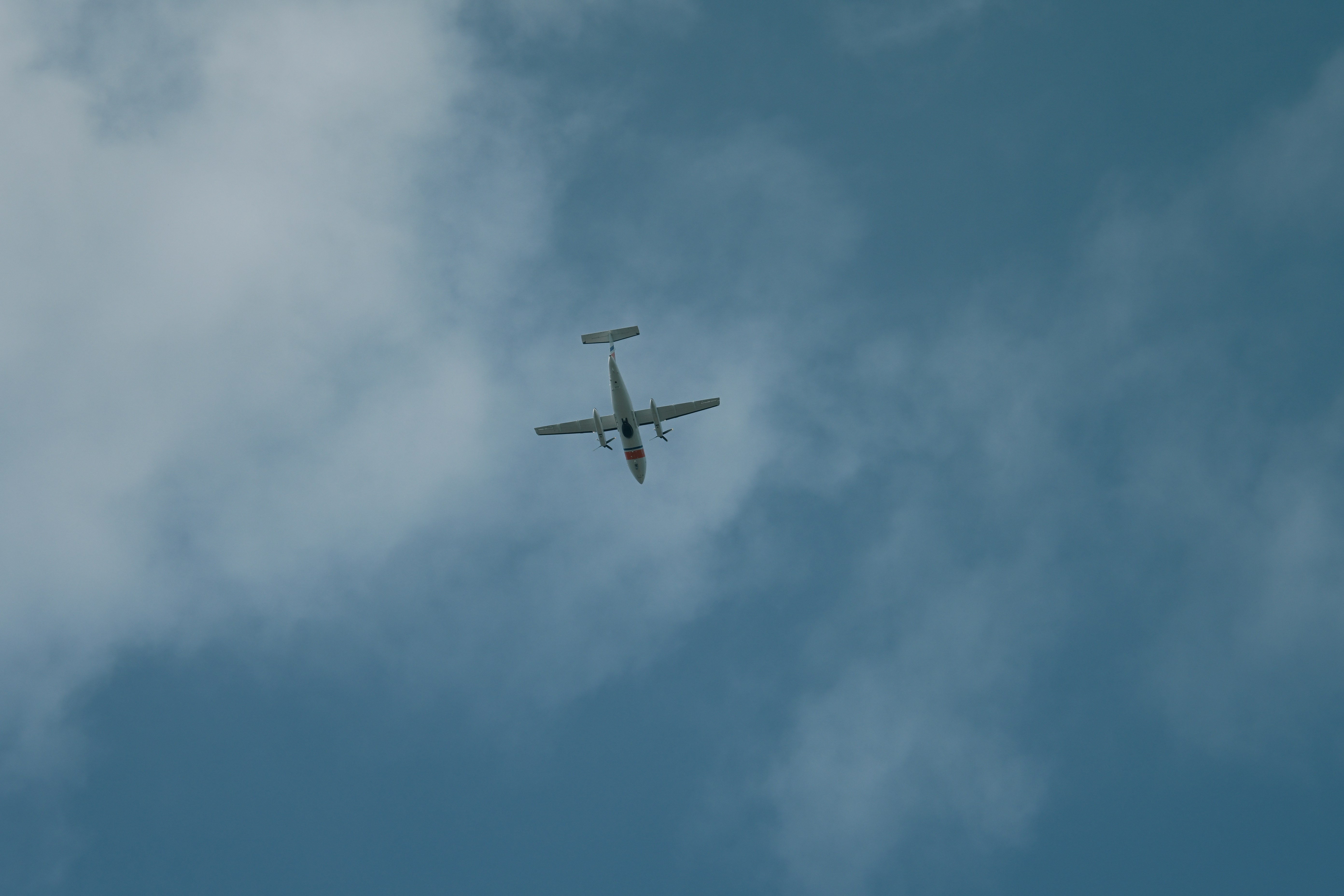 High-altitude Delivery: A lone aircraft traces a quiet path through scattered clouds