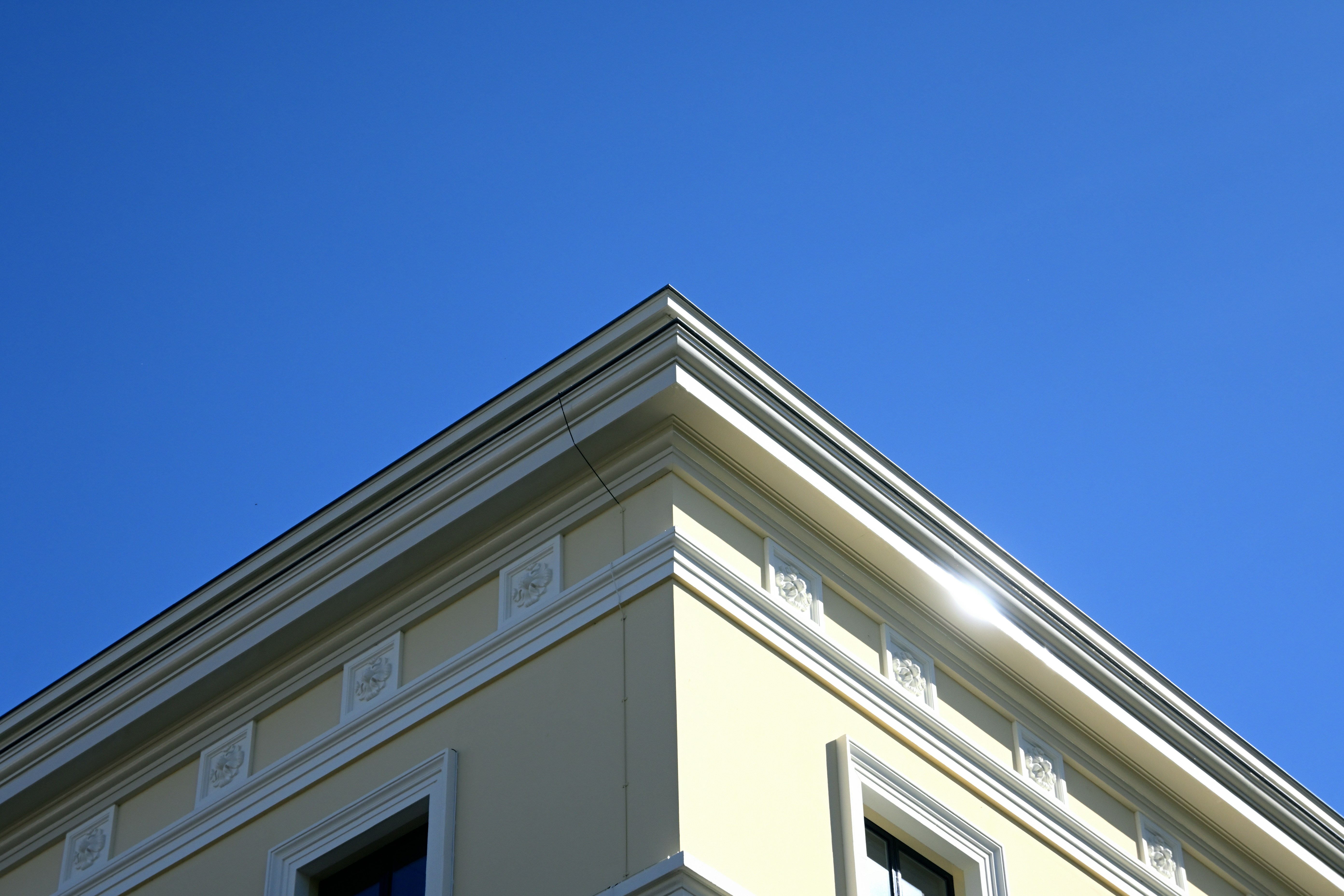 Corner of a sunlit neoclassical facade under a clear blue sky