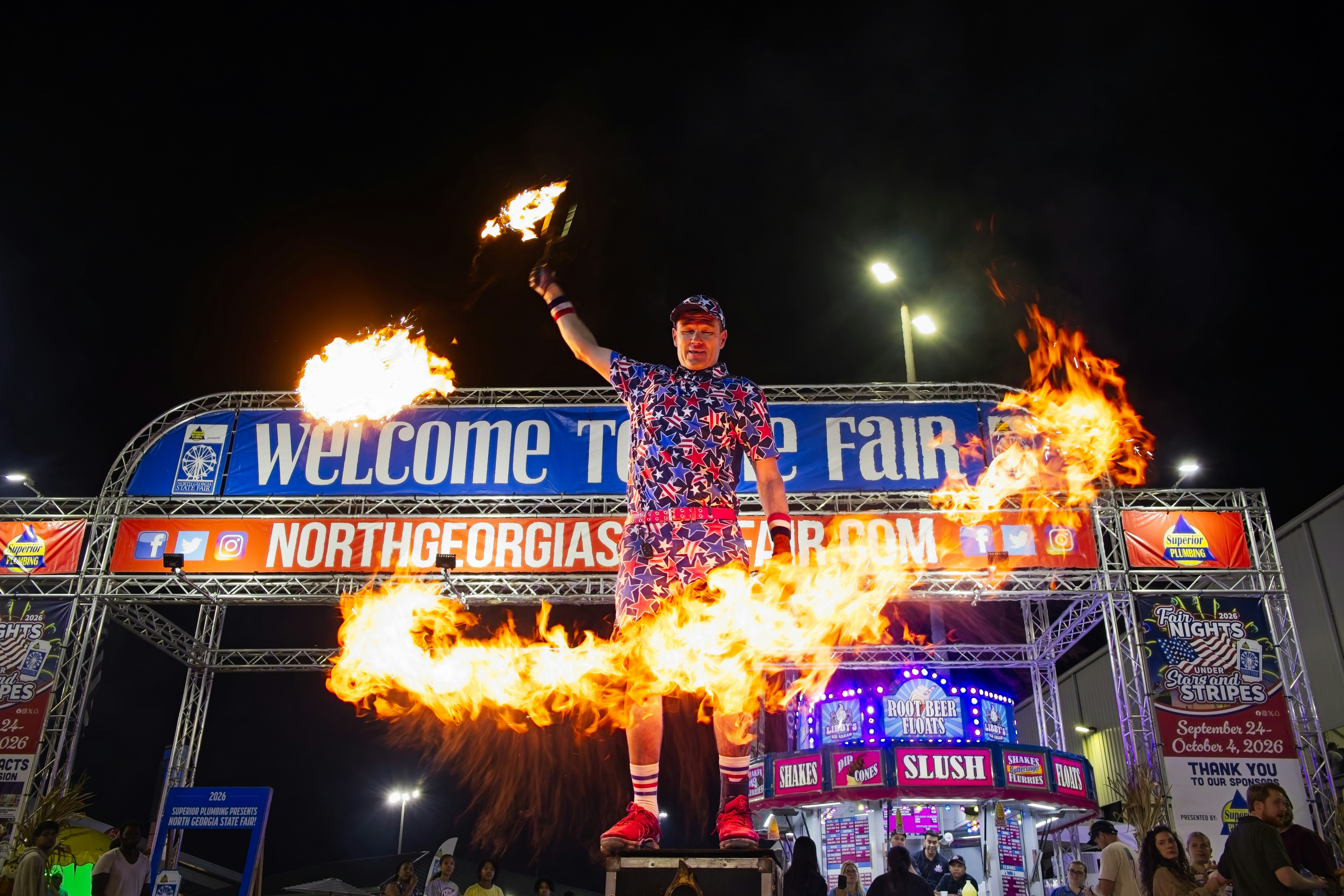 Flaming Ringmaster under Neon Lights at Welcome Fair