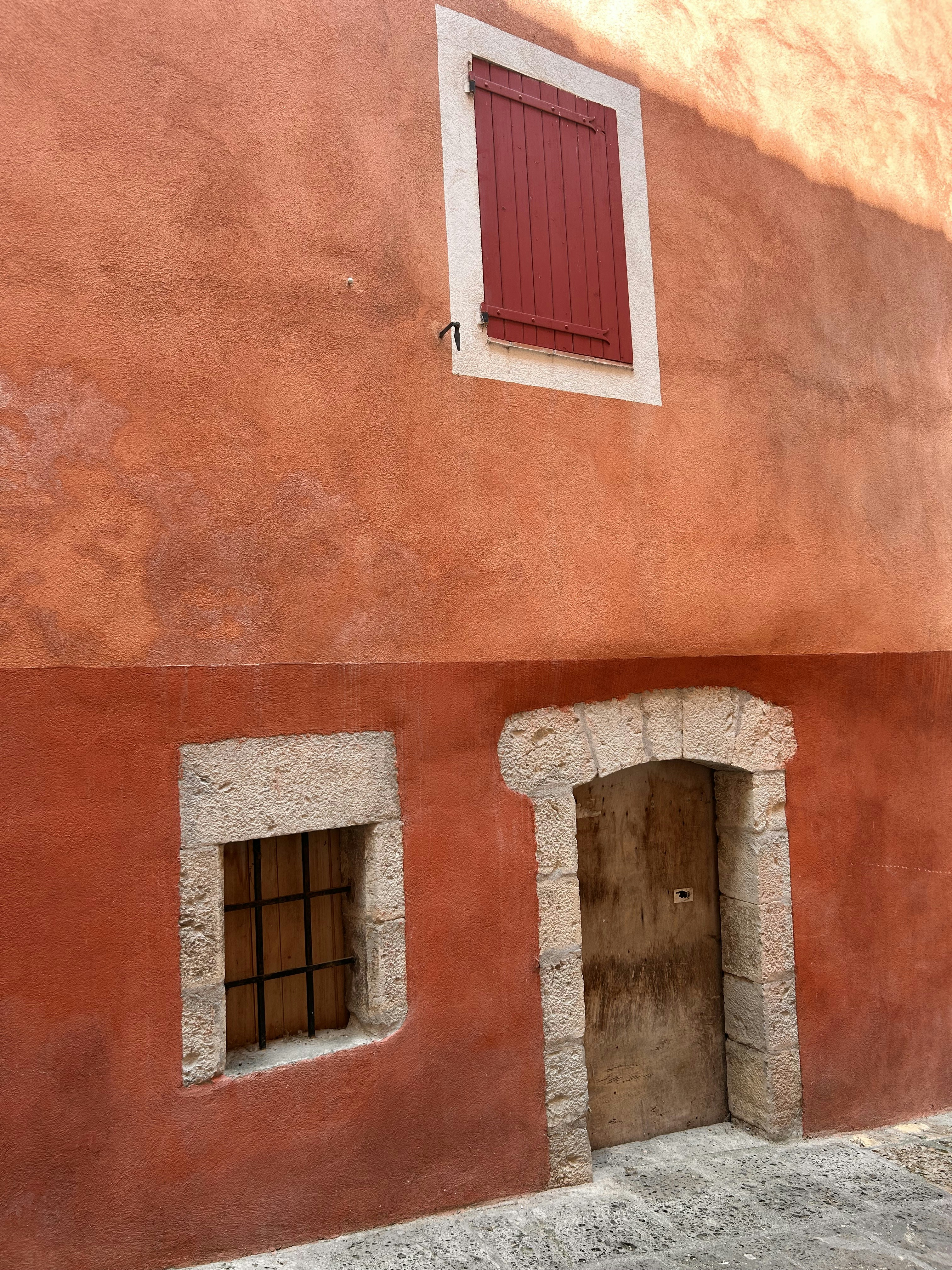 Terracotta Facade: A Quiet Archway Beneath a Red Window
