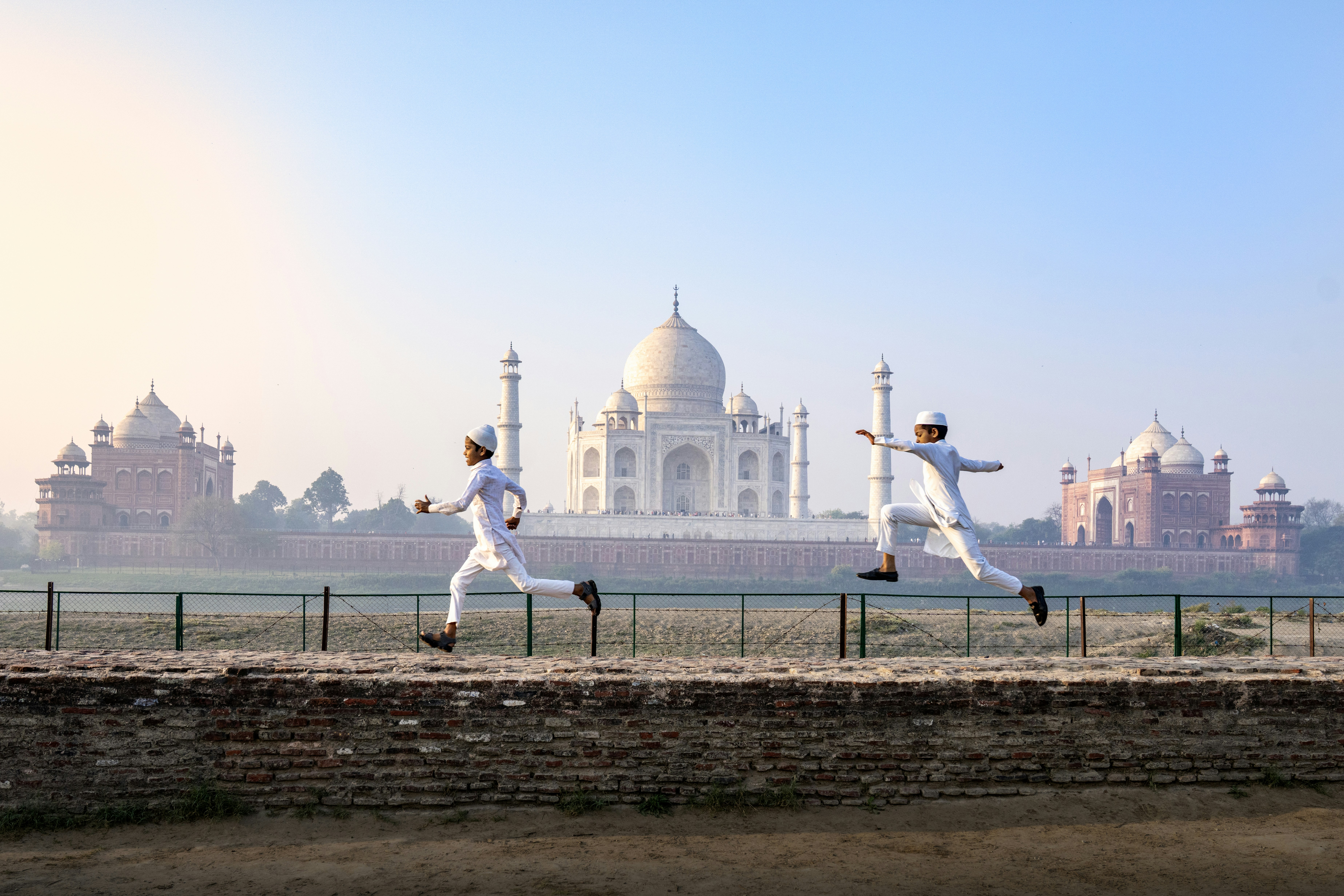 Leap of Light: Two Dancers Cross the Riverfront with the Taj Mahal in the Distance