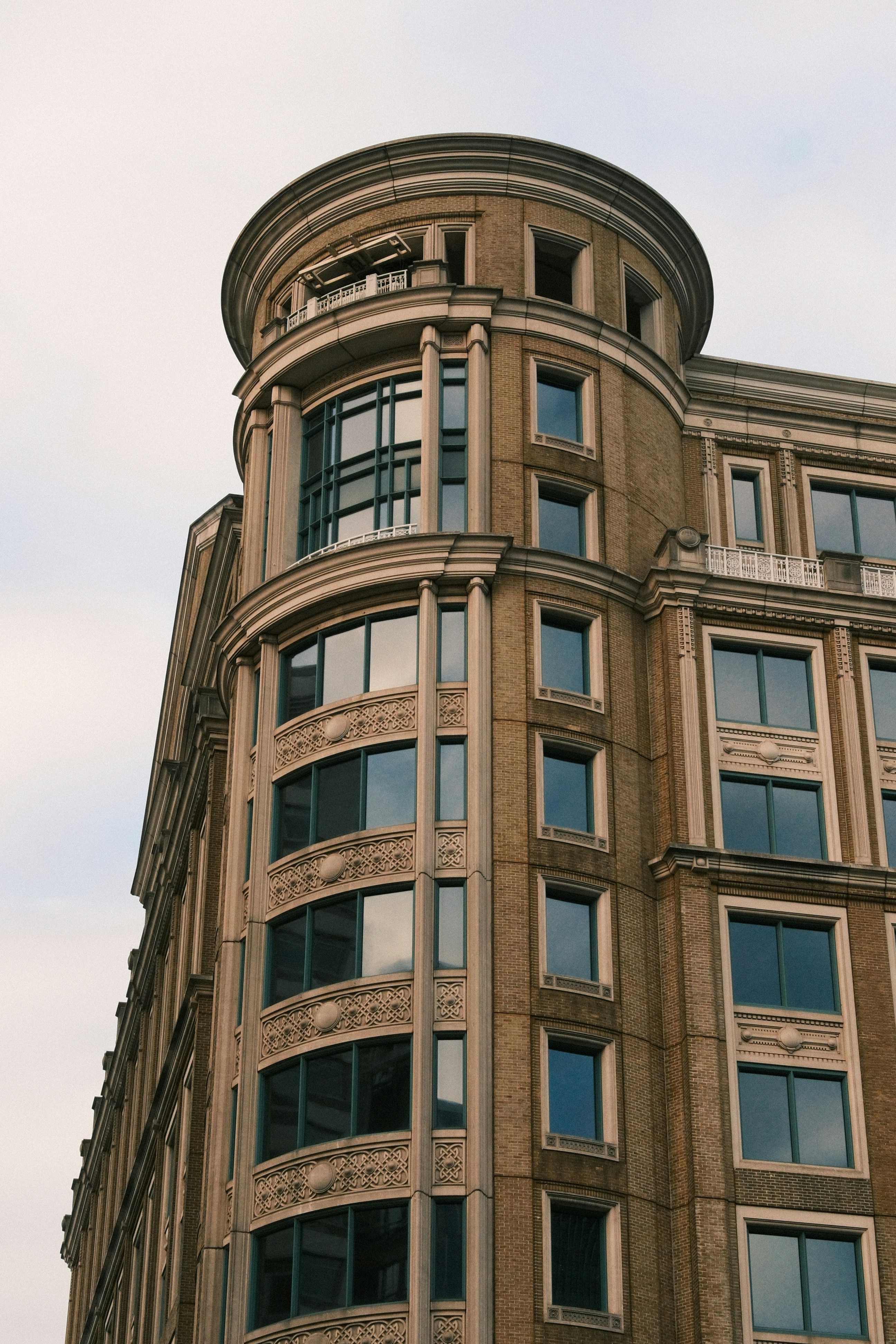 Circular turreted classic: a tan-brick corner building rising into the sky
