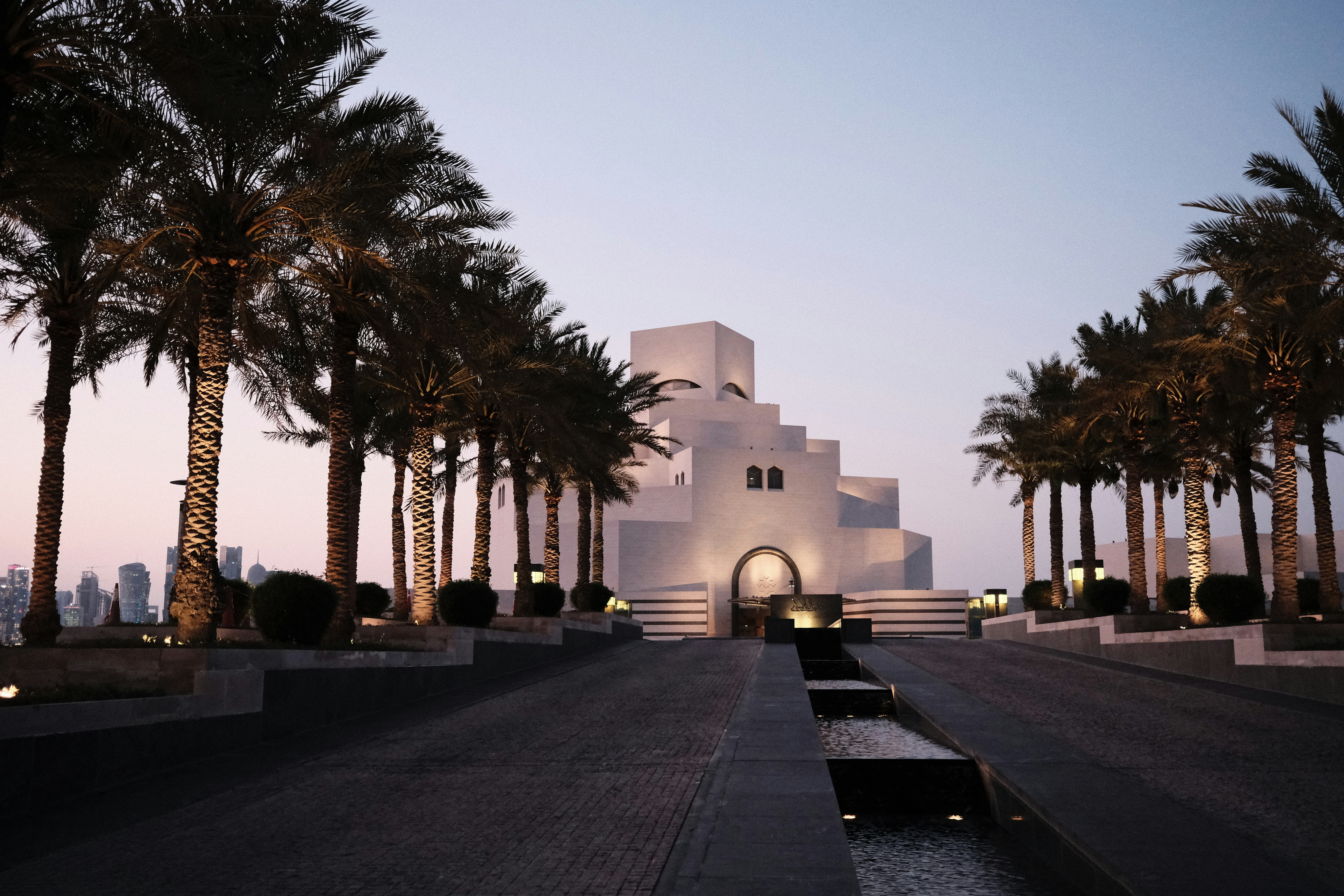 Symmetrical Alabaster Gate: Palm-lined Approach at Dusk