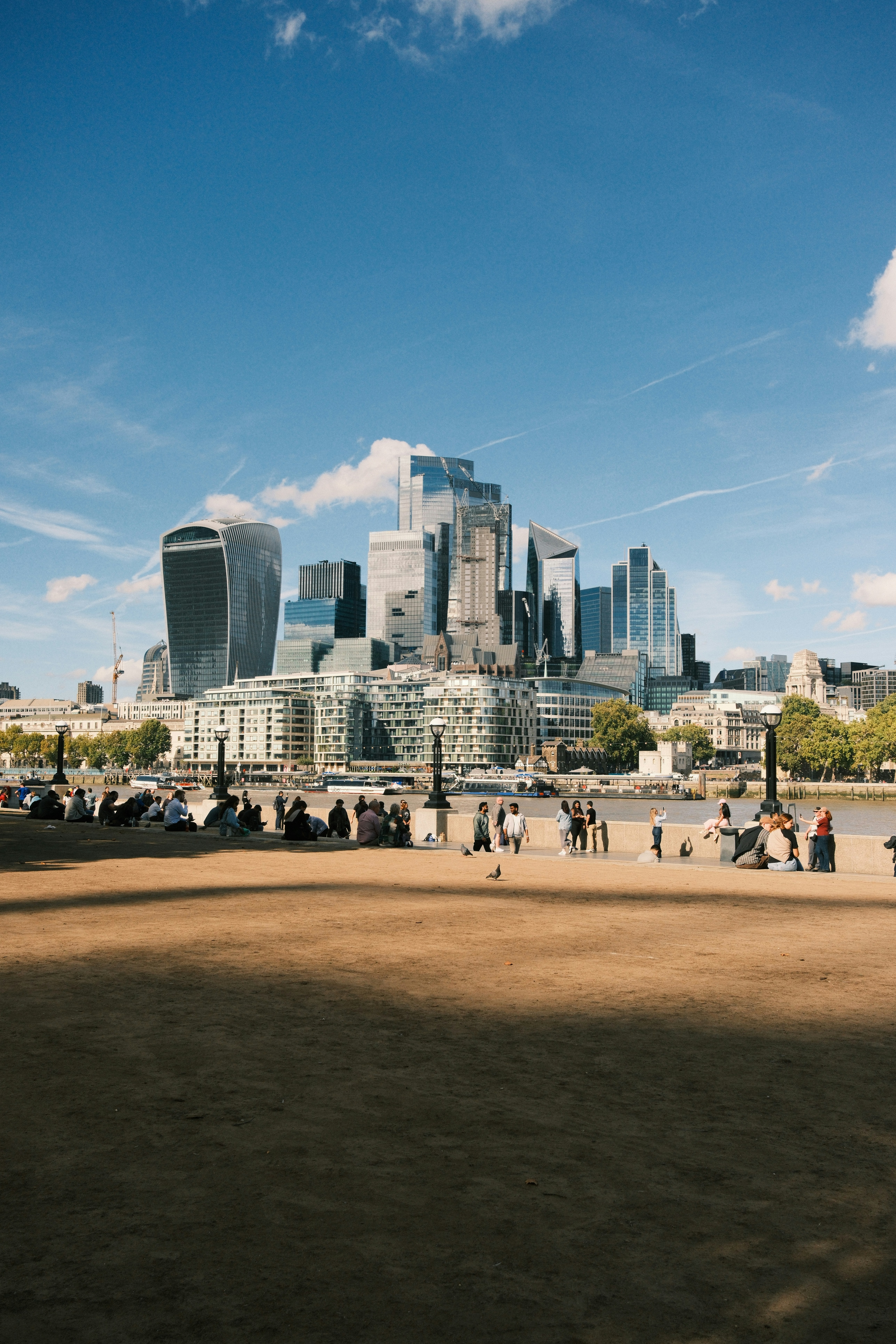 Riverside silhouettes: City skyline over a sunlit promenade