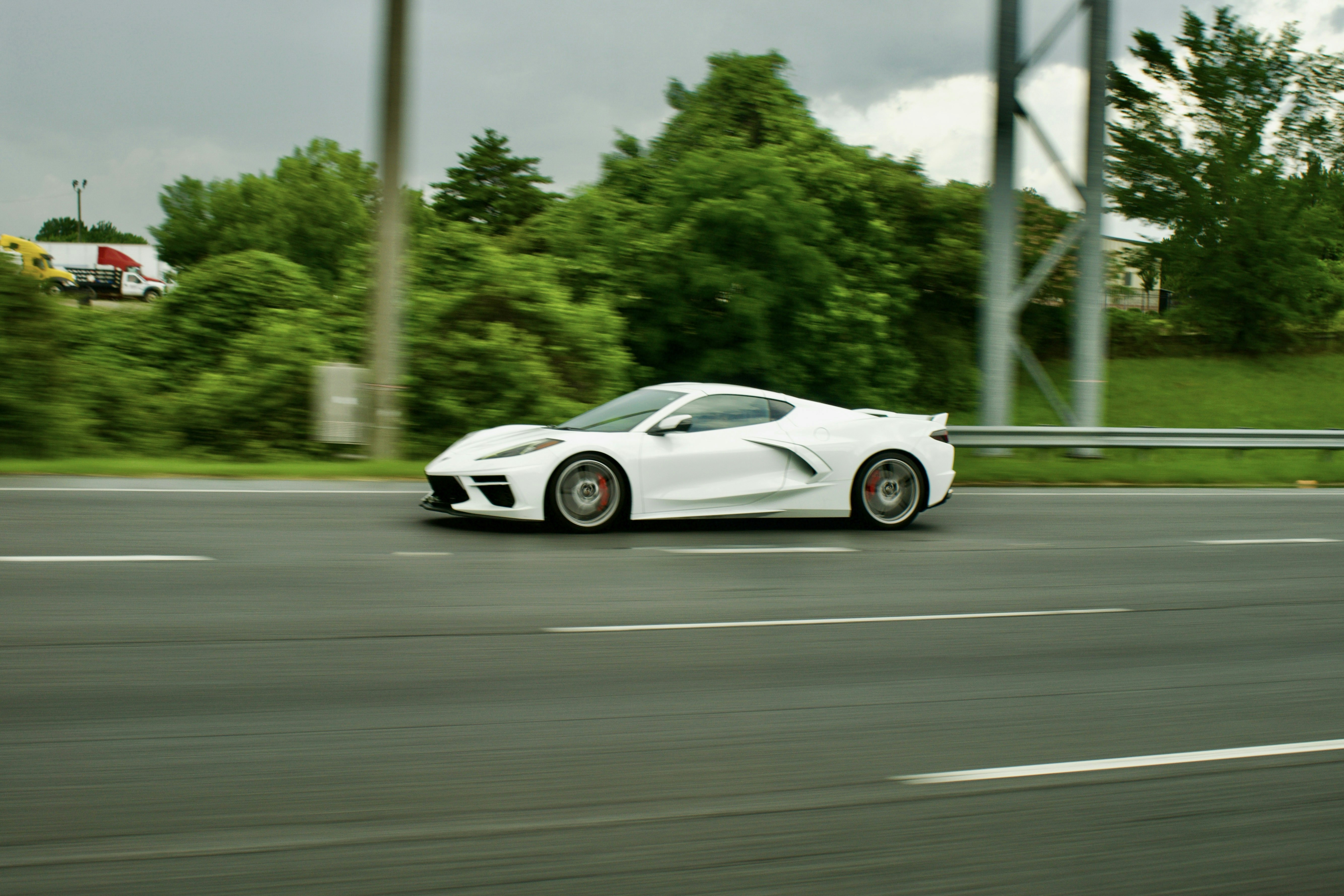 White supercar streaks past on a highway