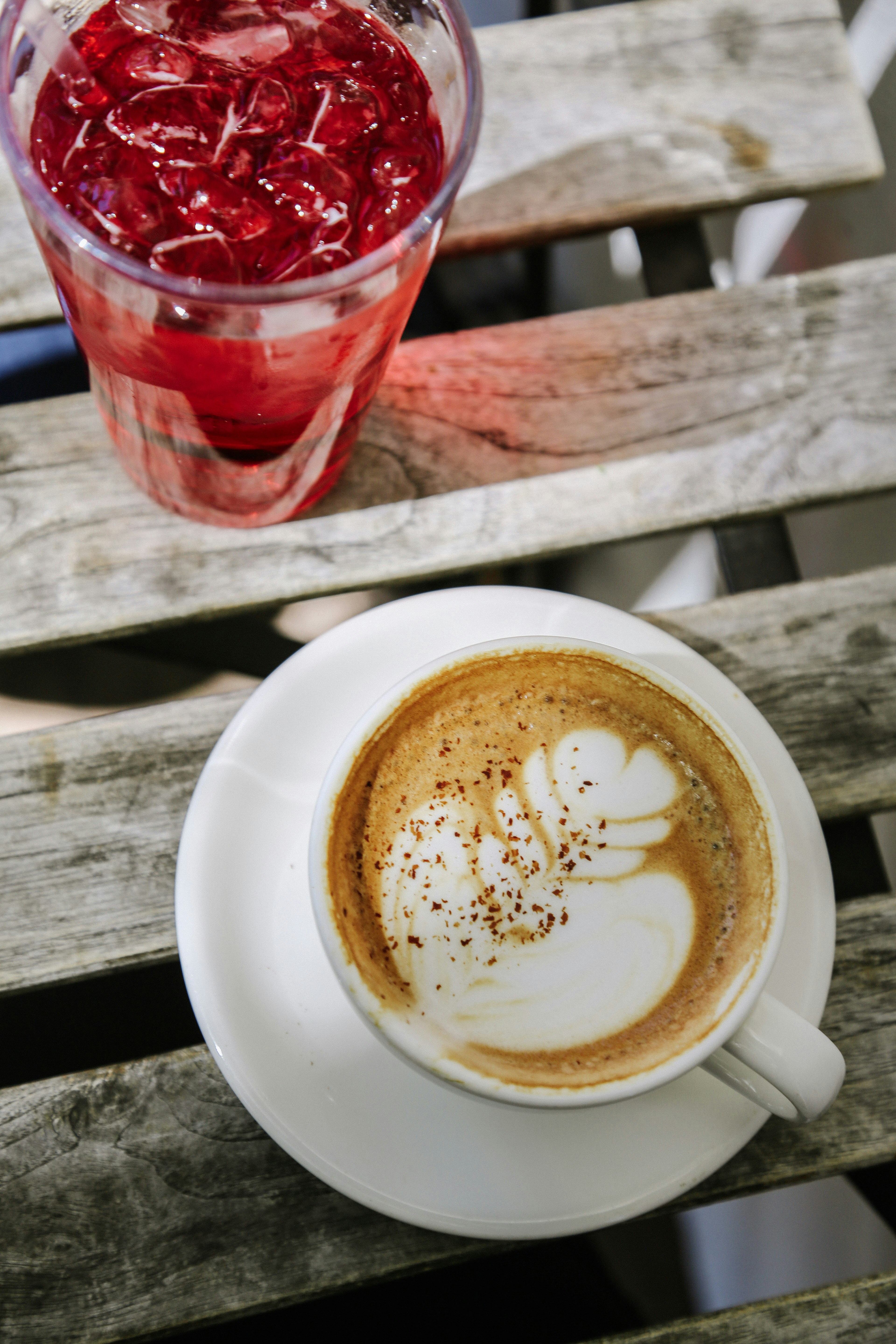 Caffeinated Texture: A Glass of Red Ice and a Latte Sketch on Weathered Wood