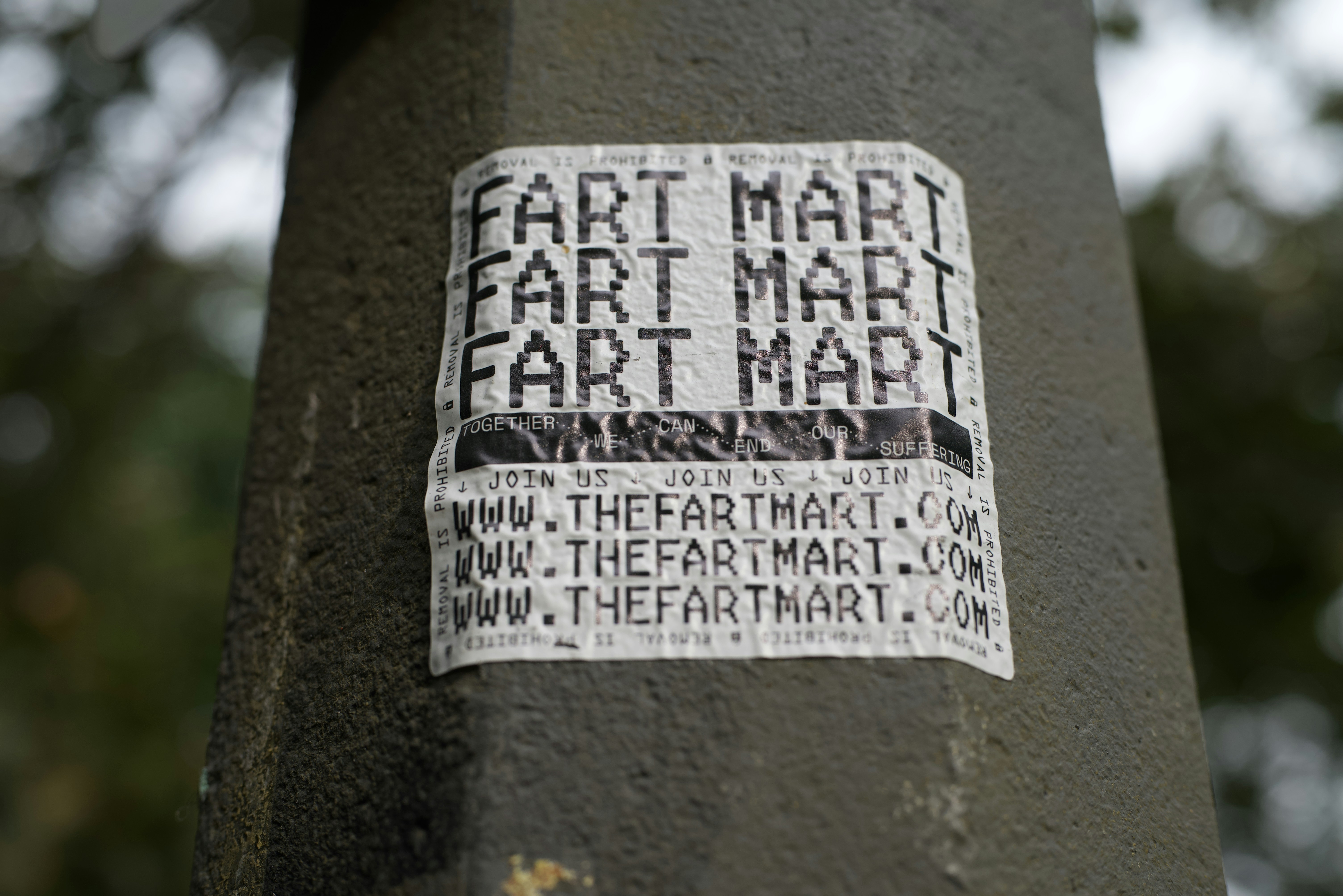 Stickered Pillar: Repetition of The Art Mart Ads Encircling a Concrete Post