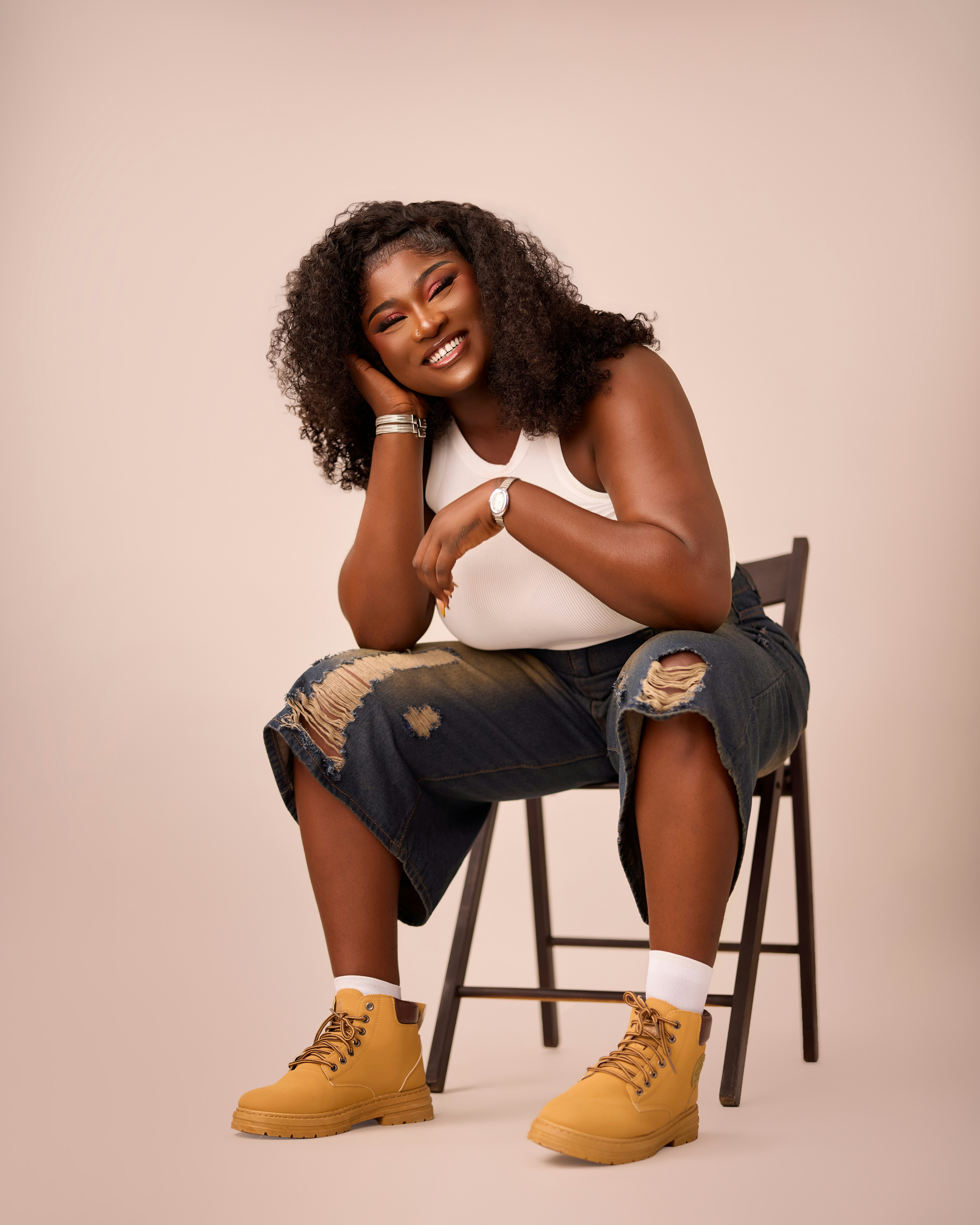 Joyful Confidence: Studio Portrait of a Woman in Distressed Denim and Golden Boots