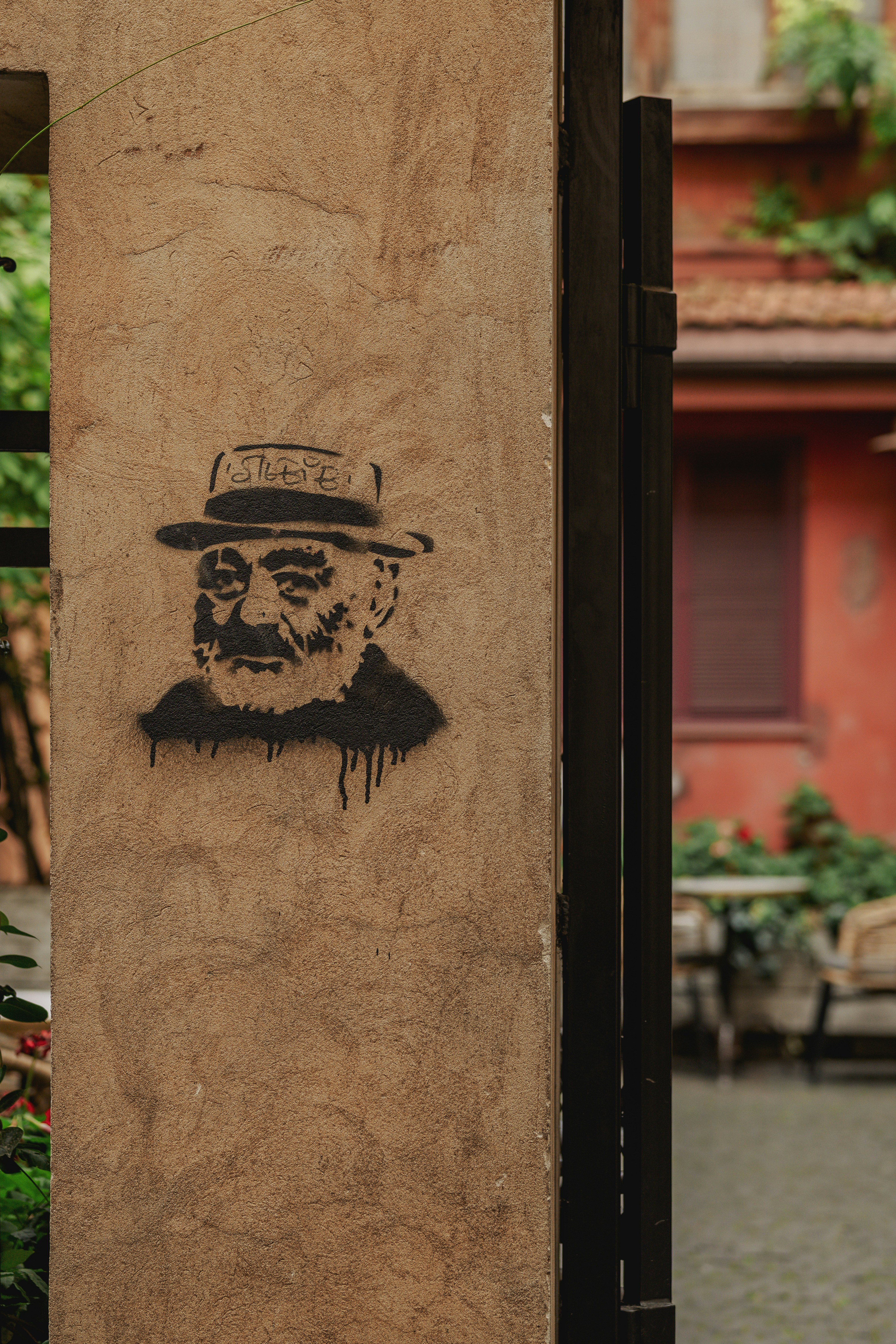 Graffiti Portrait on a Weathered Pillar Beside a Dark Gate
