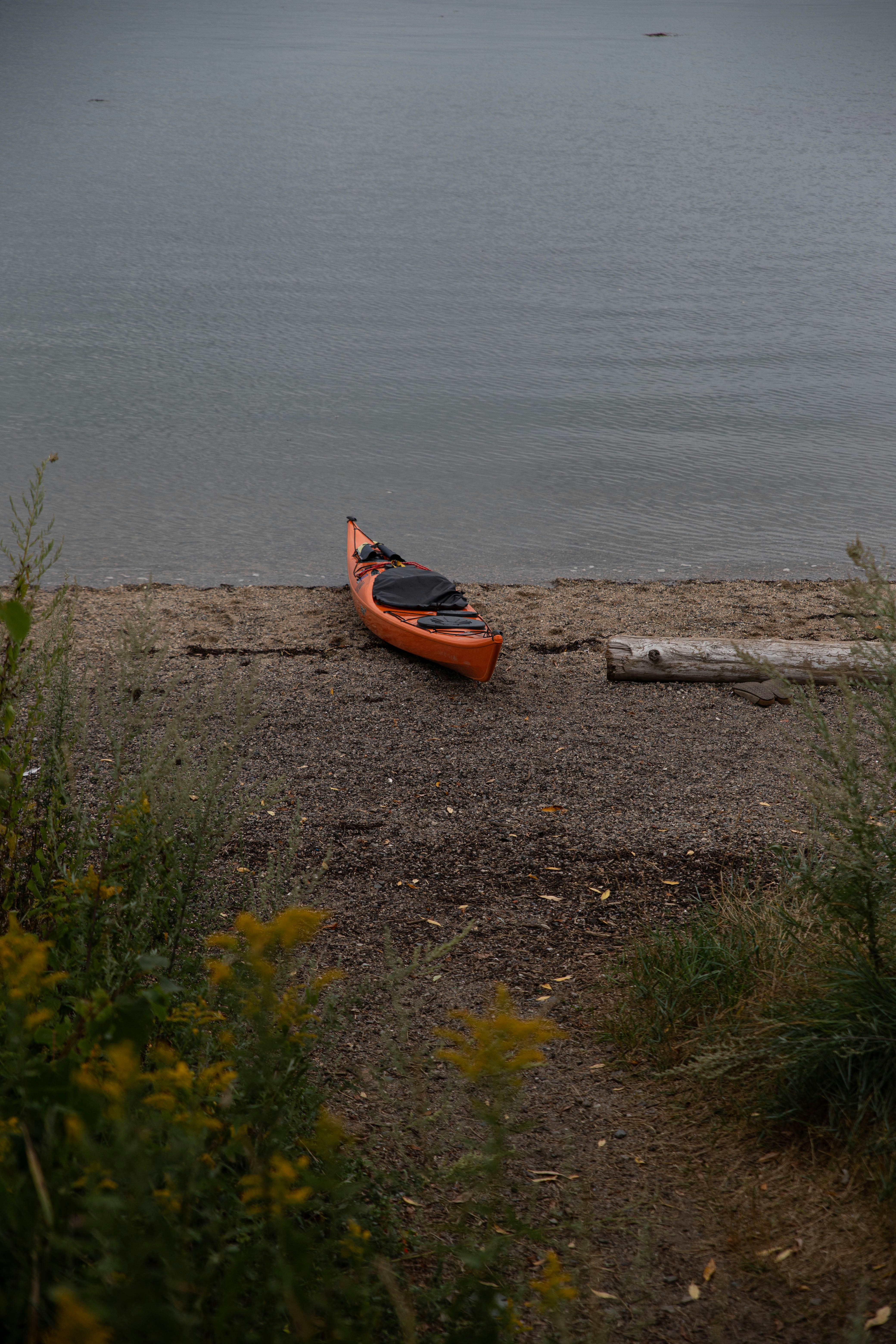 Orange Kayak on a Quiet Pebble Beach by Calm Water