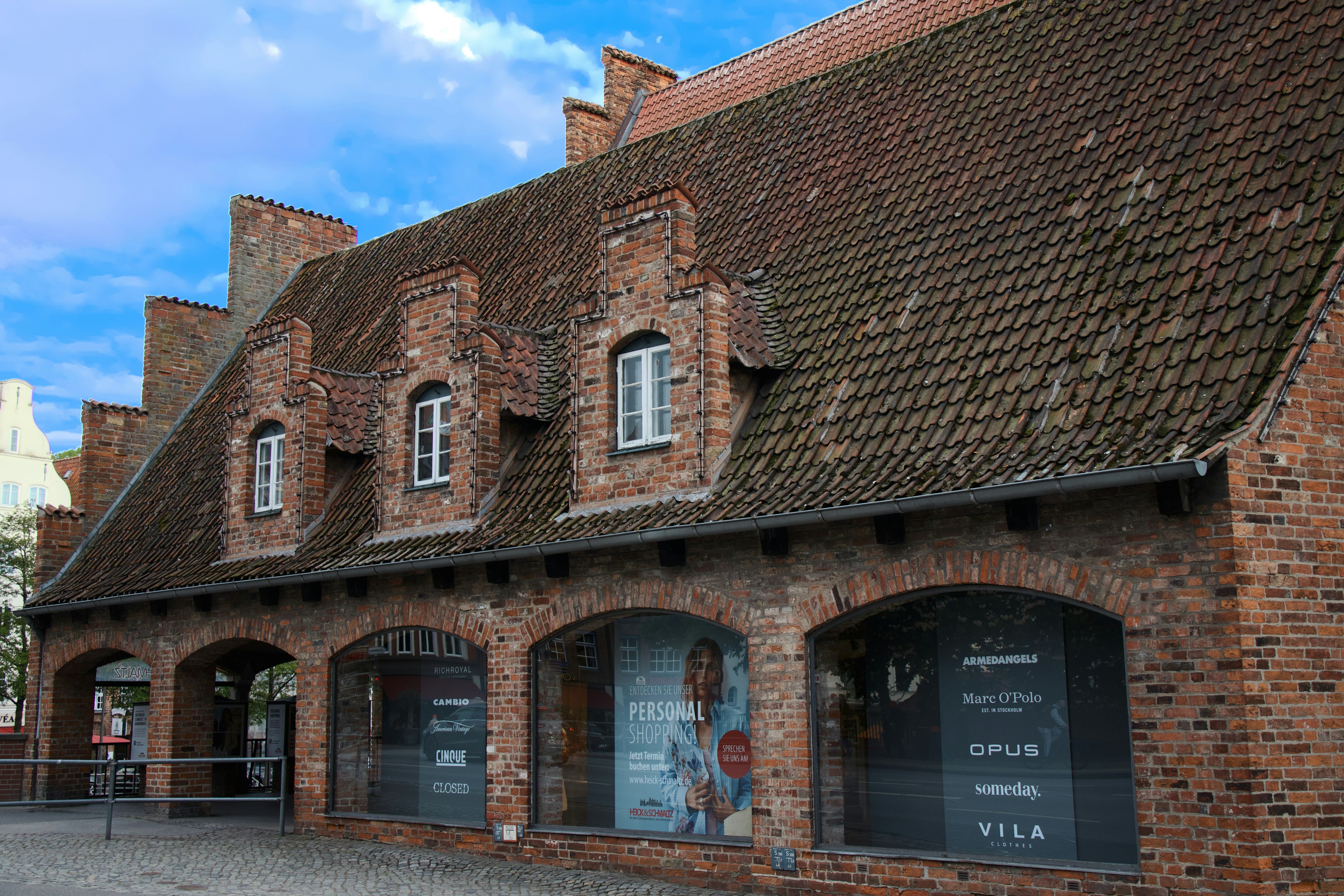 Gabled Heritage: Brick Facade and Shopfronts Under a Bluish Sky