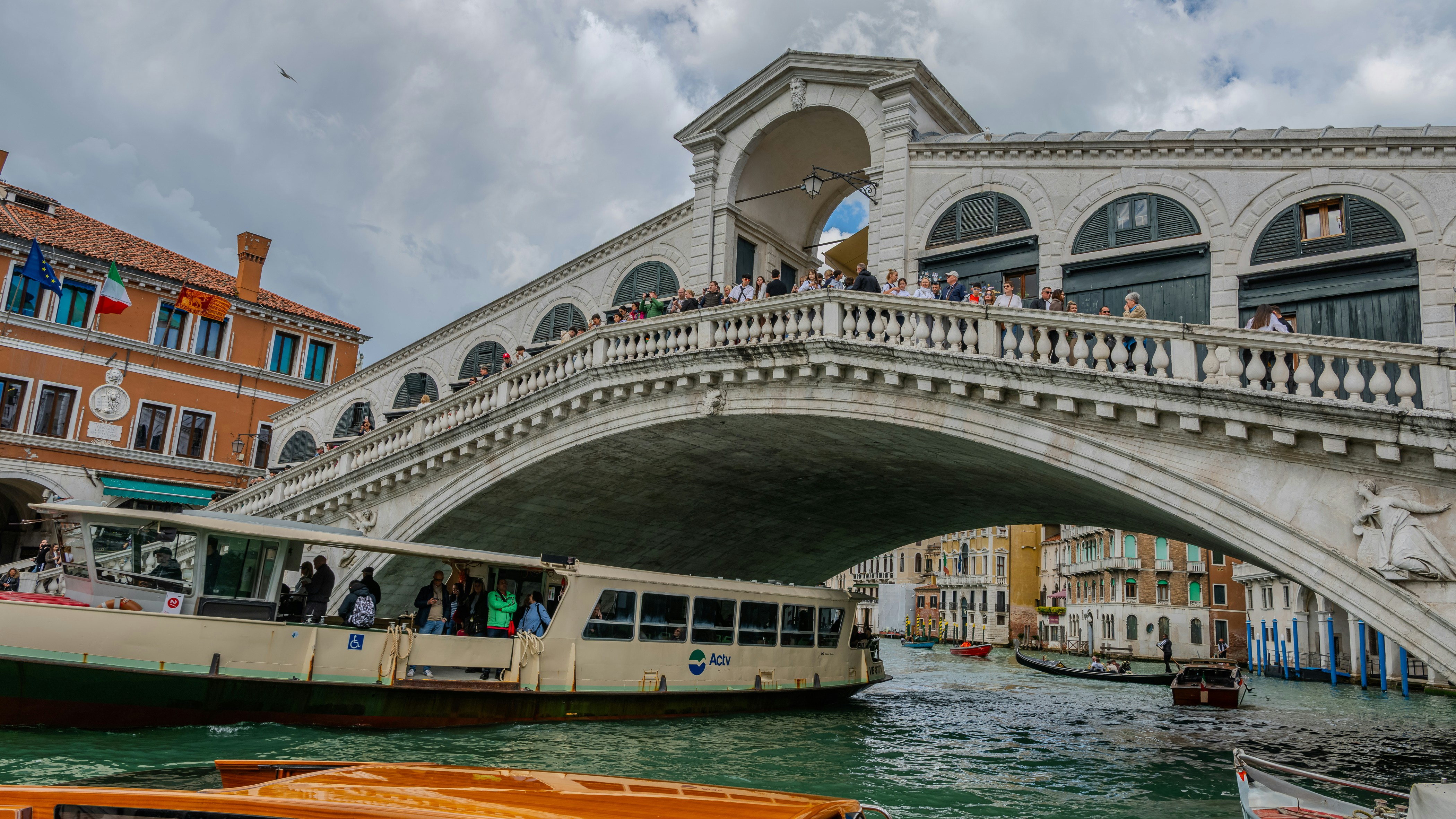 Rialto Bridge Arc: Boats and Passengers Drift Beneath Carved Stone