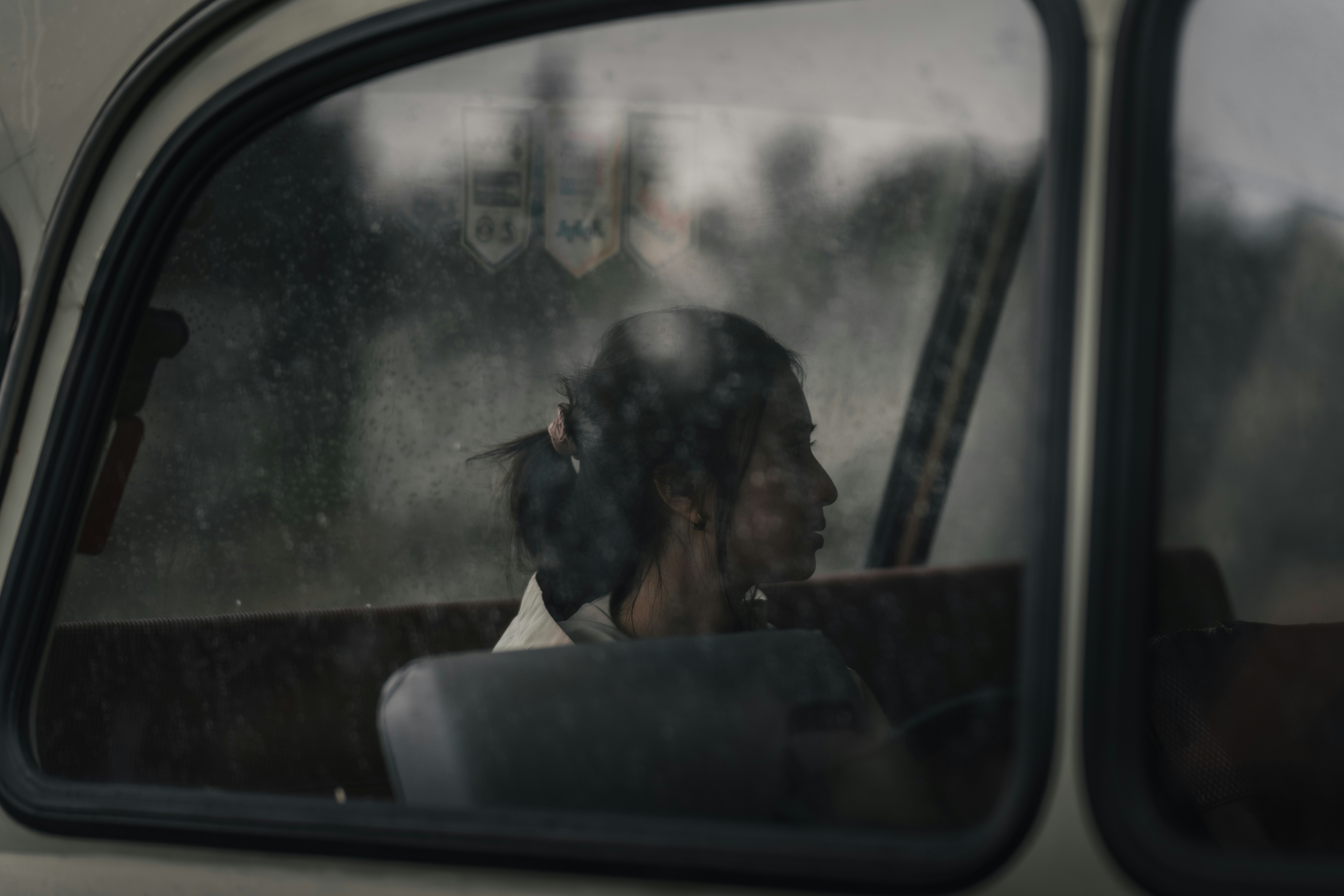 Passenger in a Rain-Streaked Window: Quiet Portrait in a Classic Car