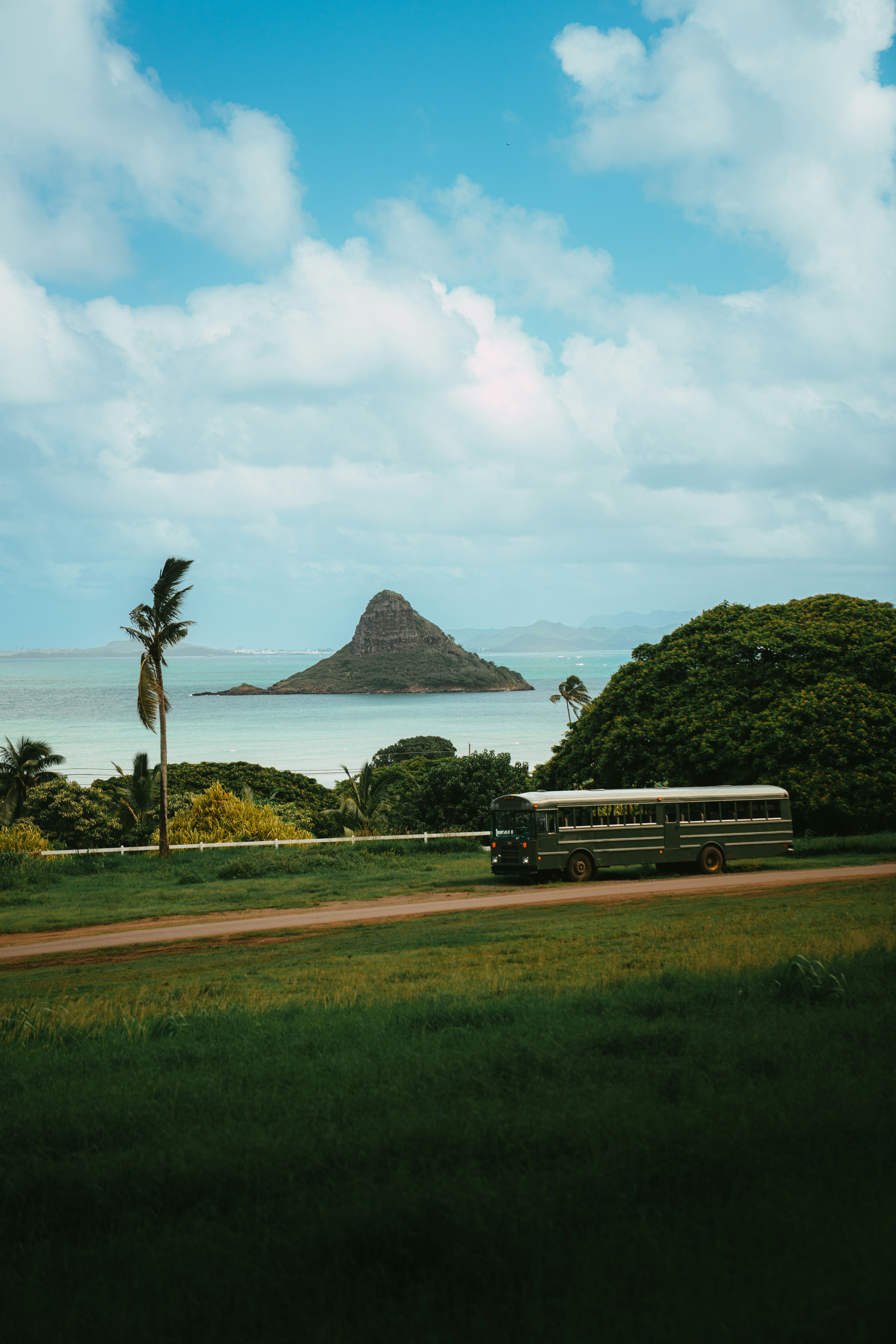 Island Eye: A distant peak guards a tranquil lagoon as a bus rolls by
