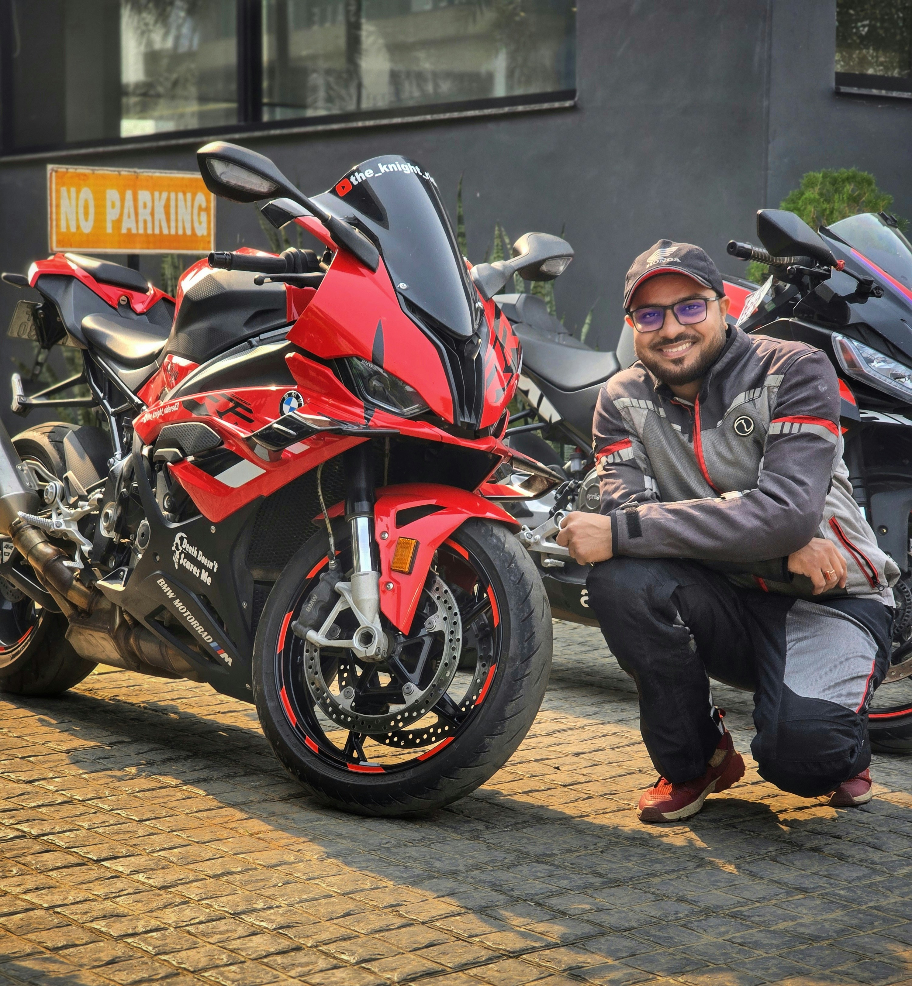 Speed and Smile: Rider Beside a Red Sports Bike in an Urban Lot