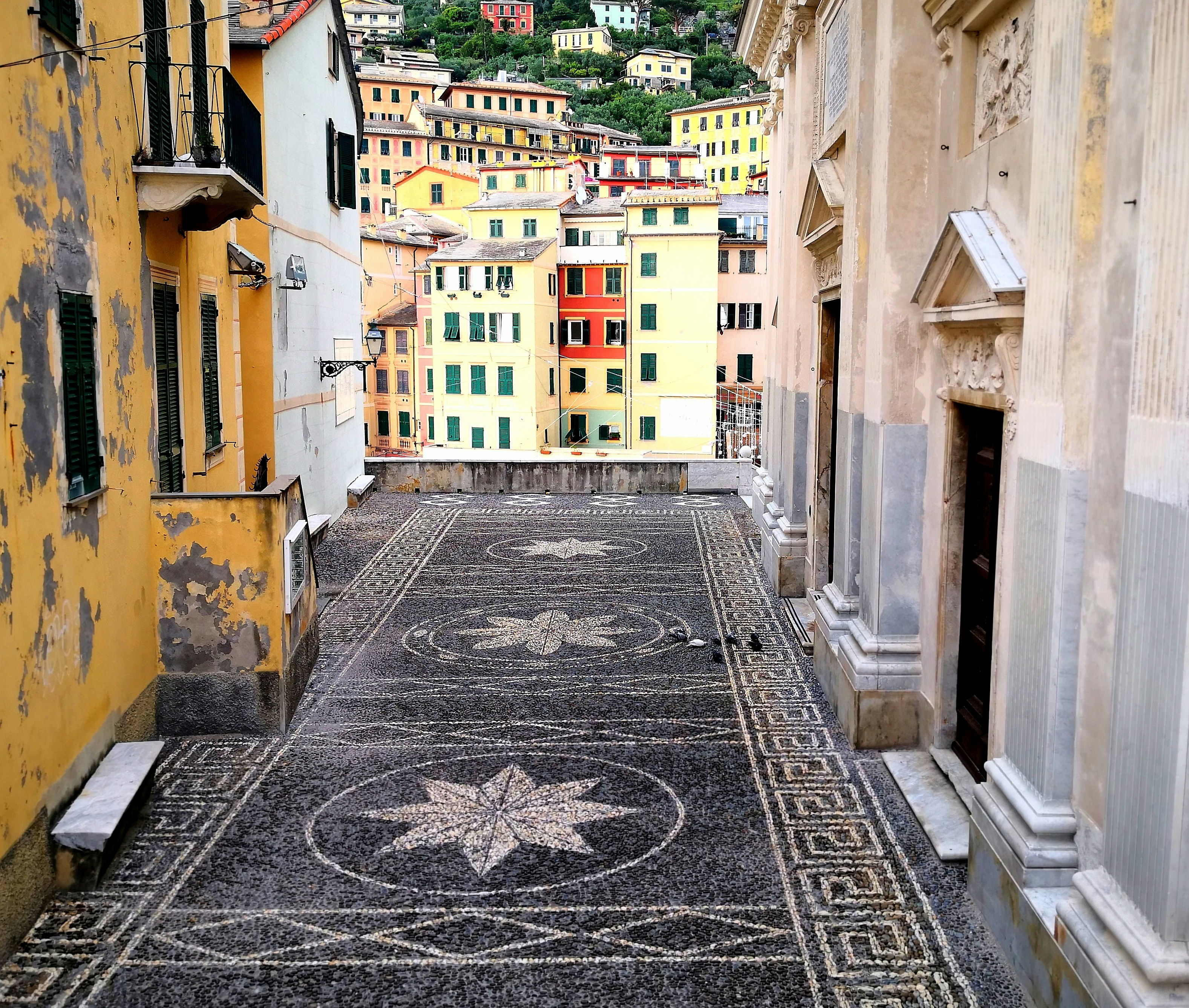 Bright houses line a steep Italian stairway with geometric pavement