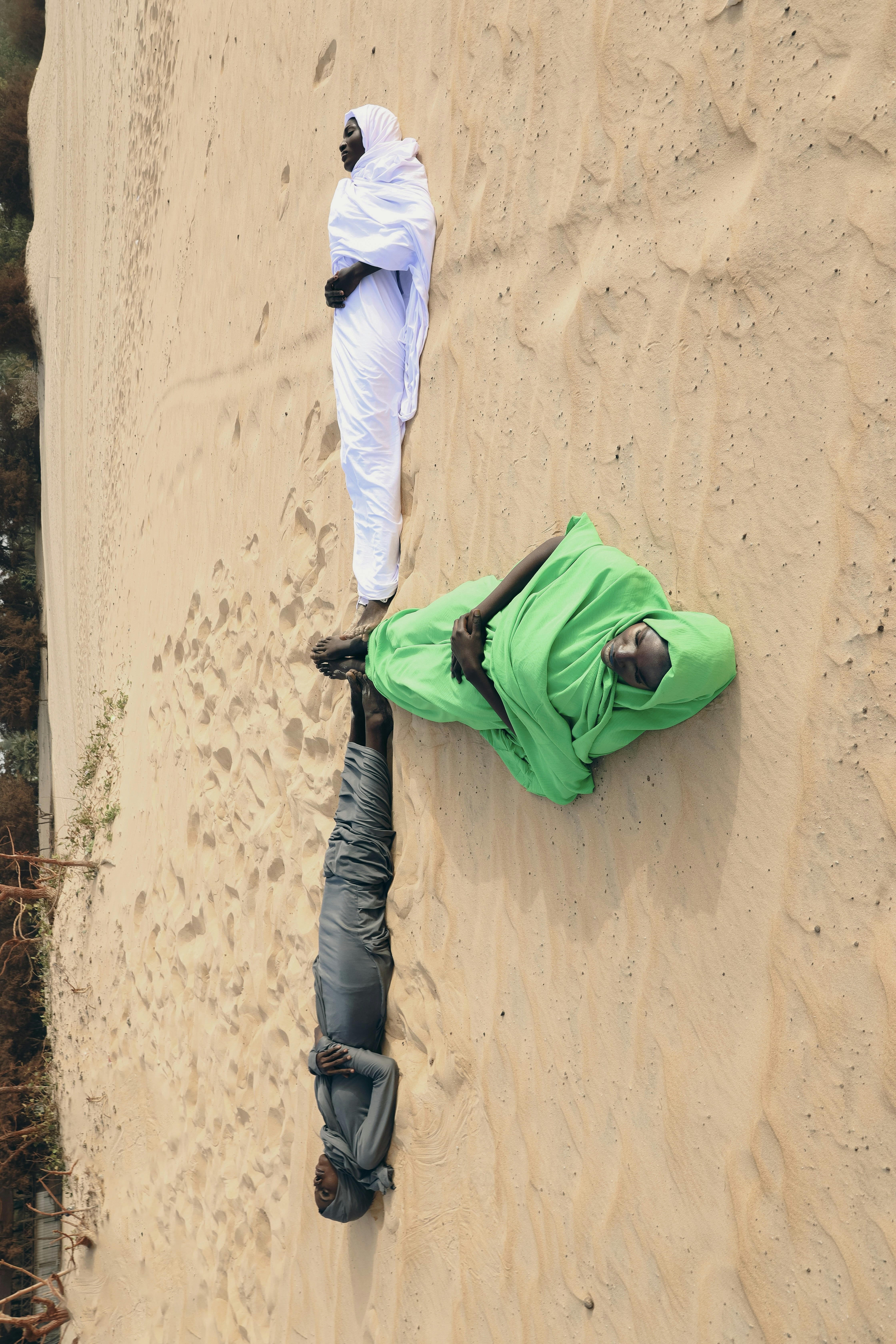 Triptych on Sand: Three Climbers in Colored Swaddles Stranded on a Dune