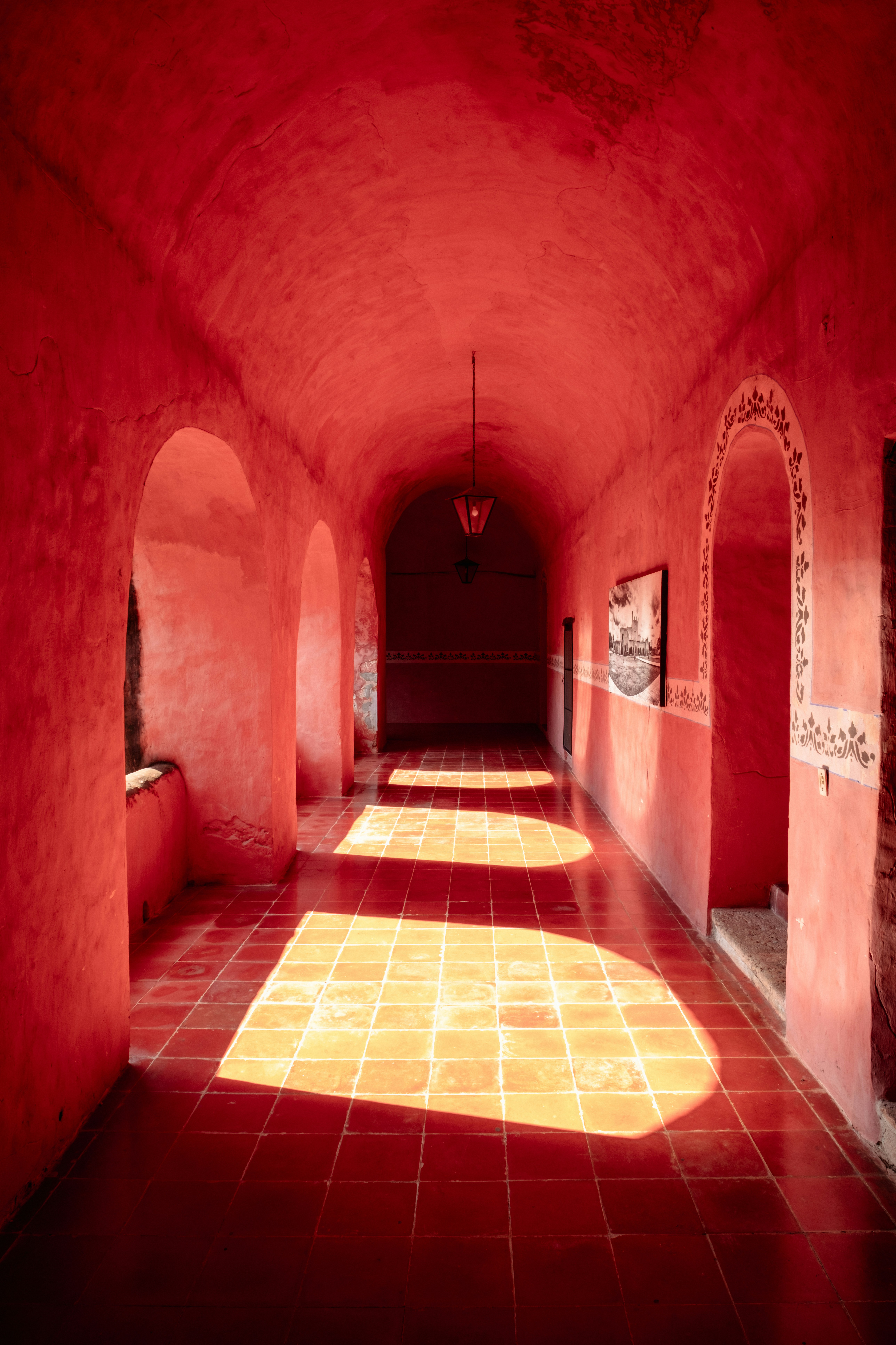 Red Corridor: Sunlit Arches of a Deserted Passage
