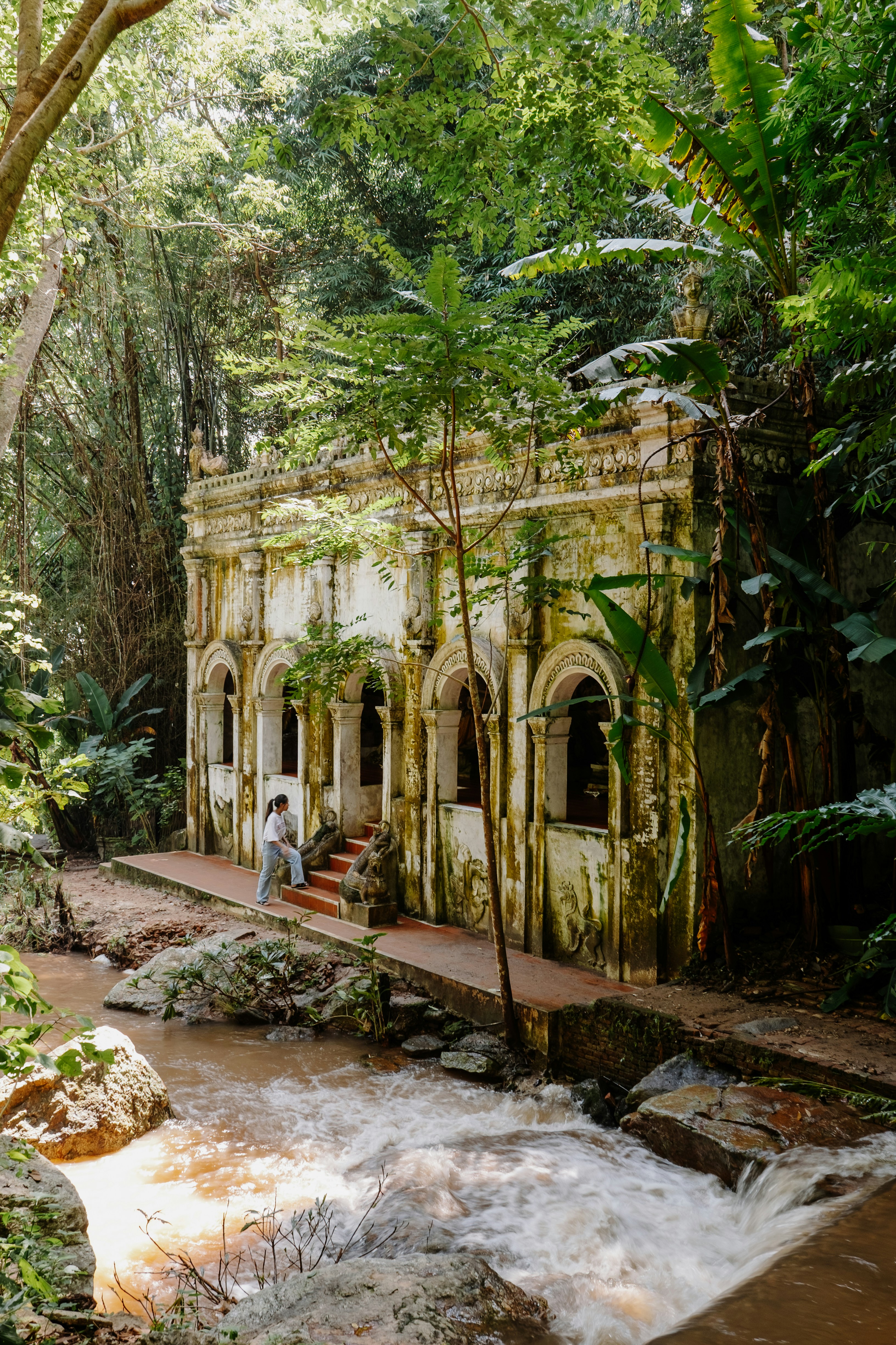 Mossy ruins by a rushing stream: a quiet moment beside an old arches building