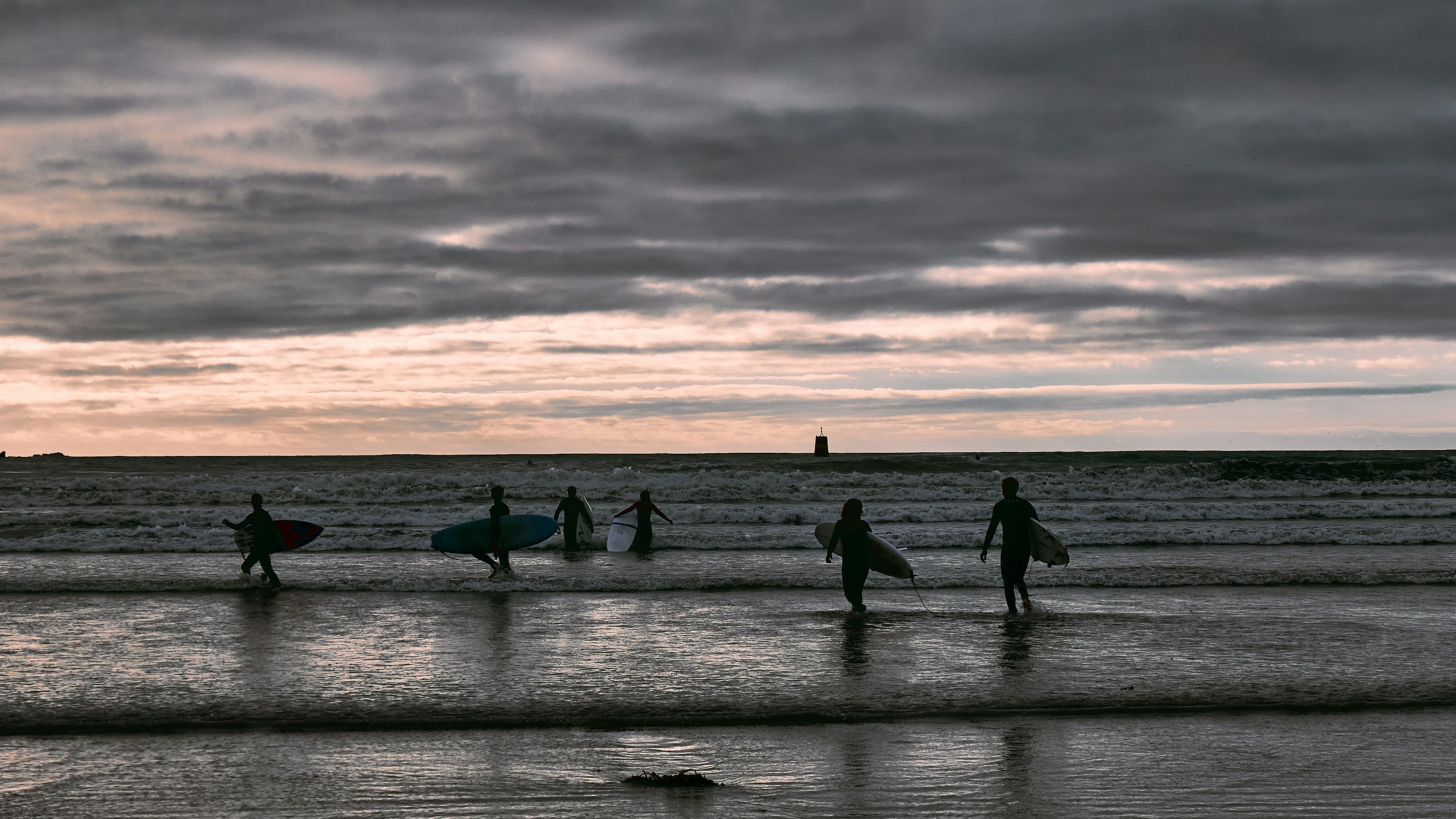 Silhouette of Surfers at Dusk: A Quiet Lineup Waiting for the Wave
