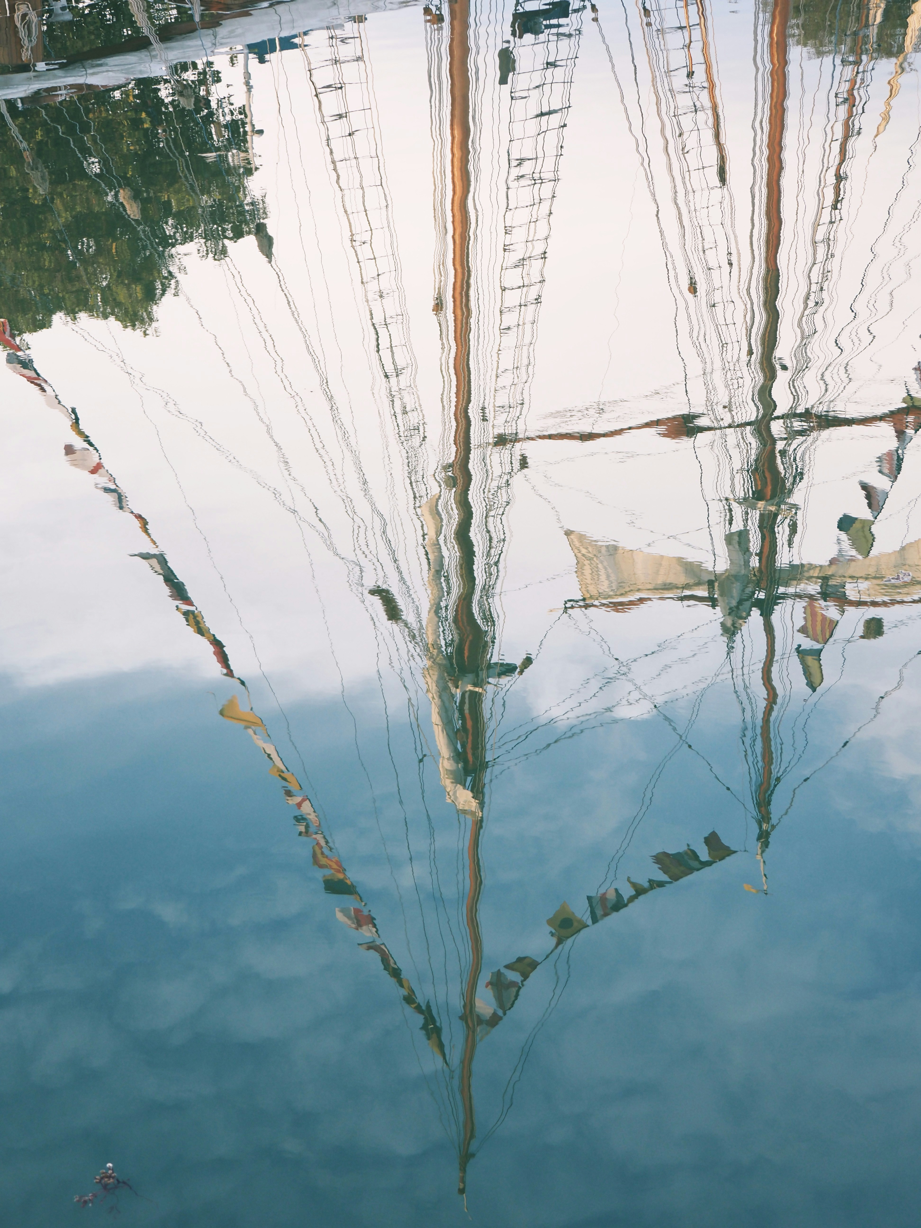 Floating Masts: Sailboat Reflections across a Quiet Channel