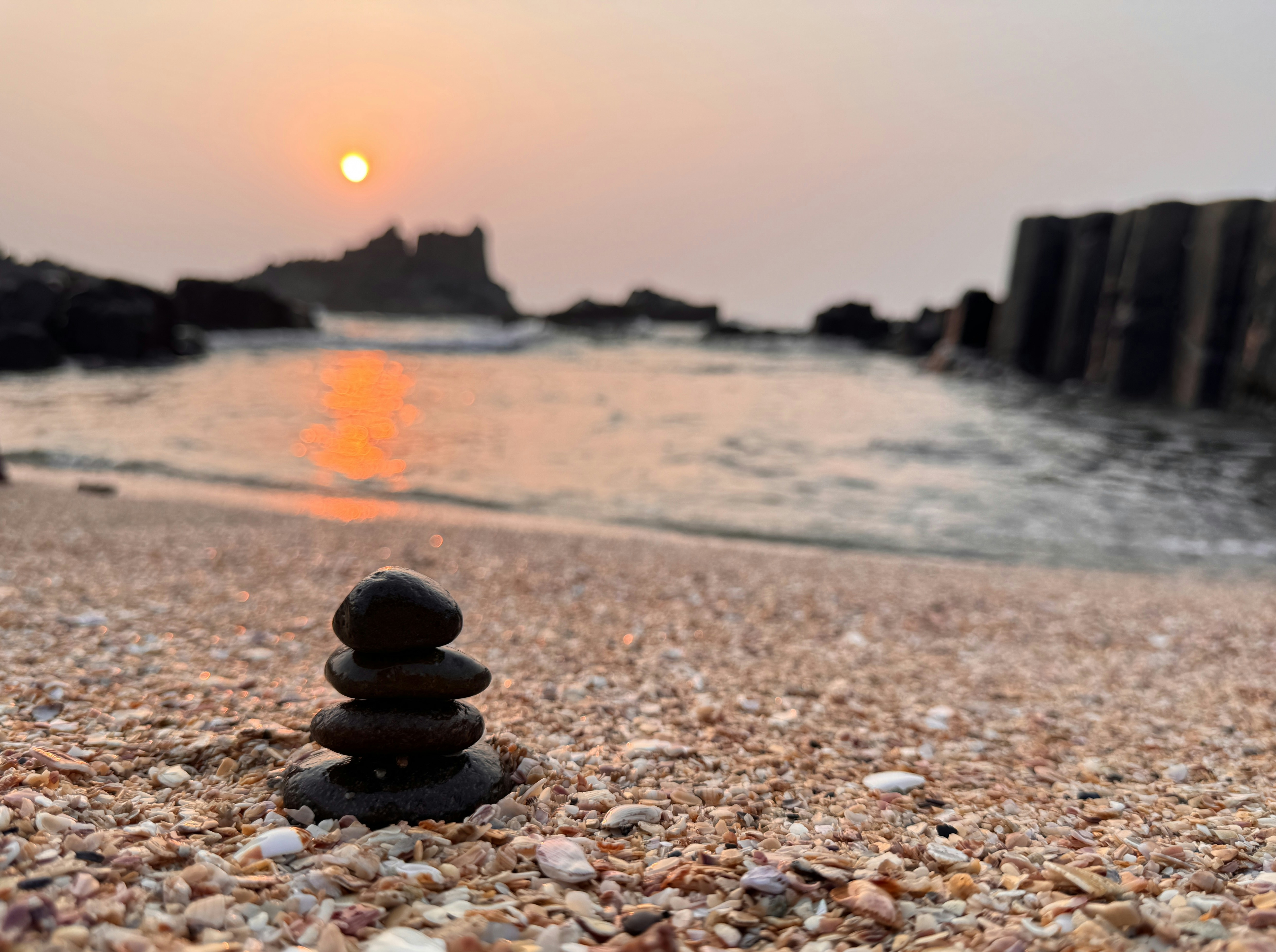 Zen on the Shore: Stacked Pebbles and a Fiery Tide