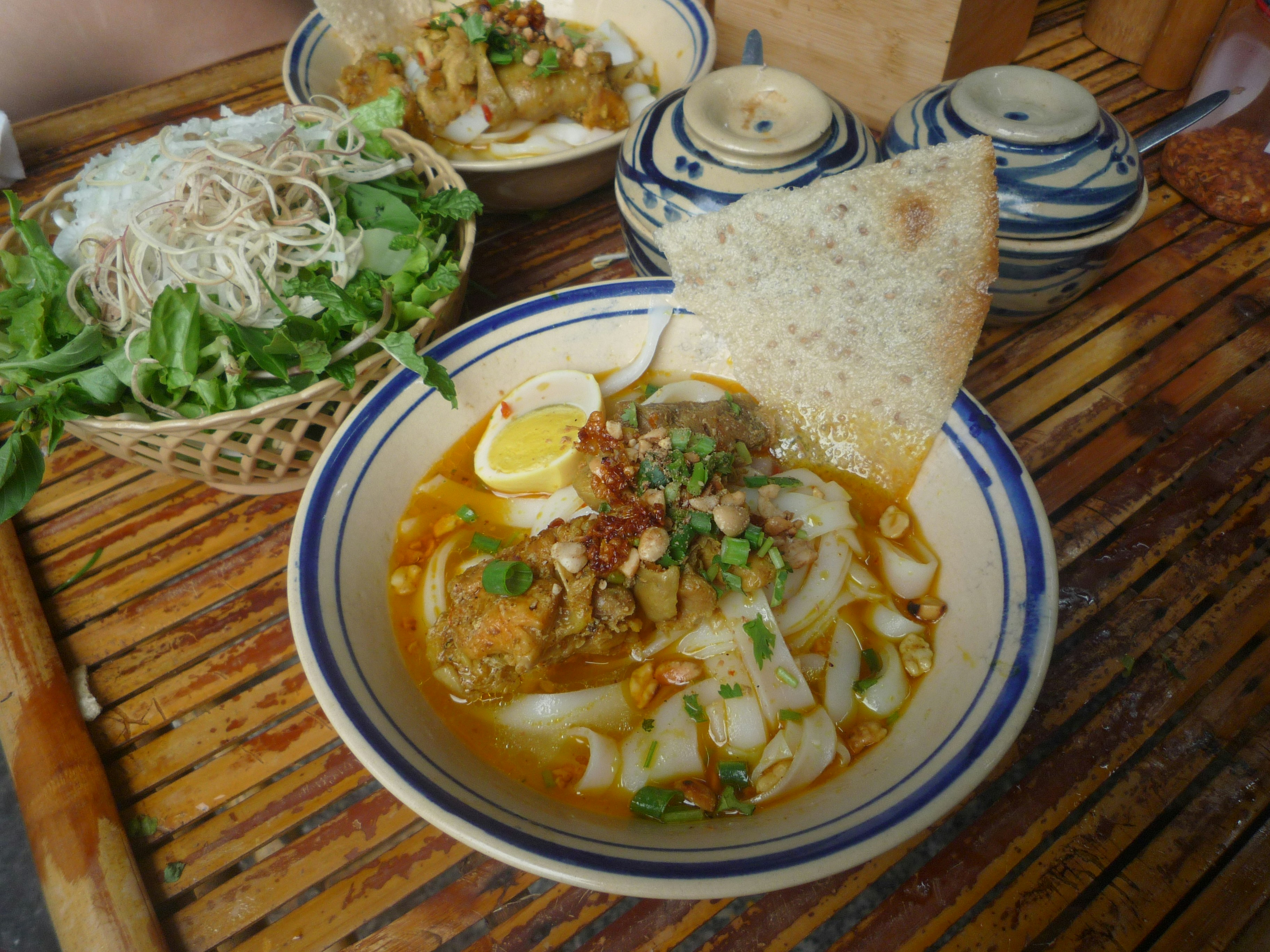Spiced Noodle Bowl with Crispy Bread and Garnished Greens