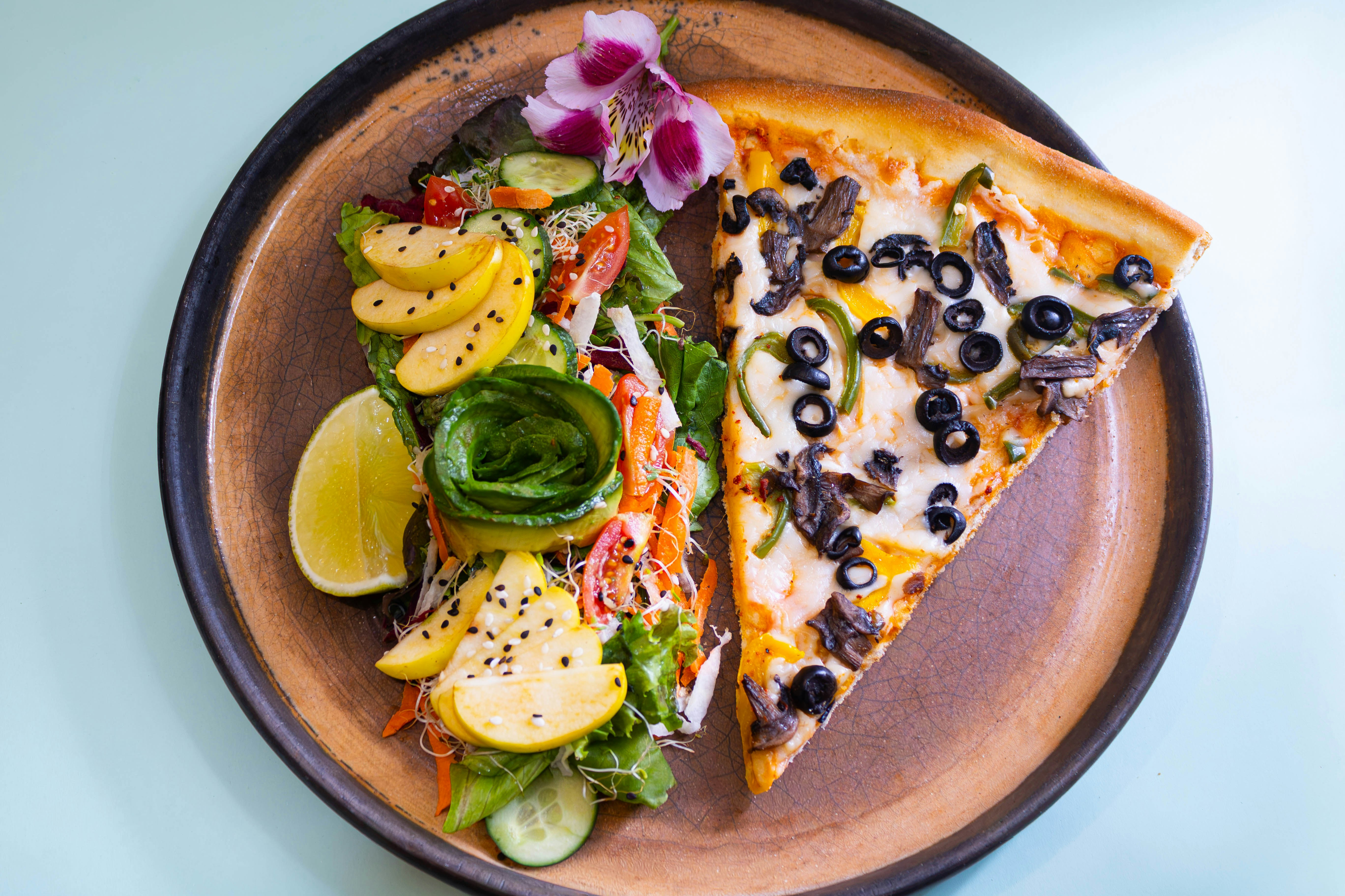 Citrus-green Salad with Olive-Ted Pizza Slice on a Rustic Plate
