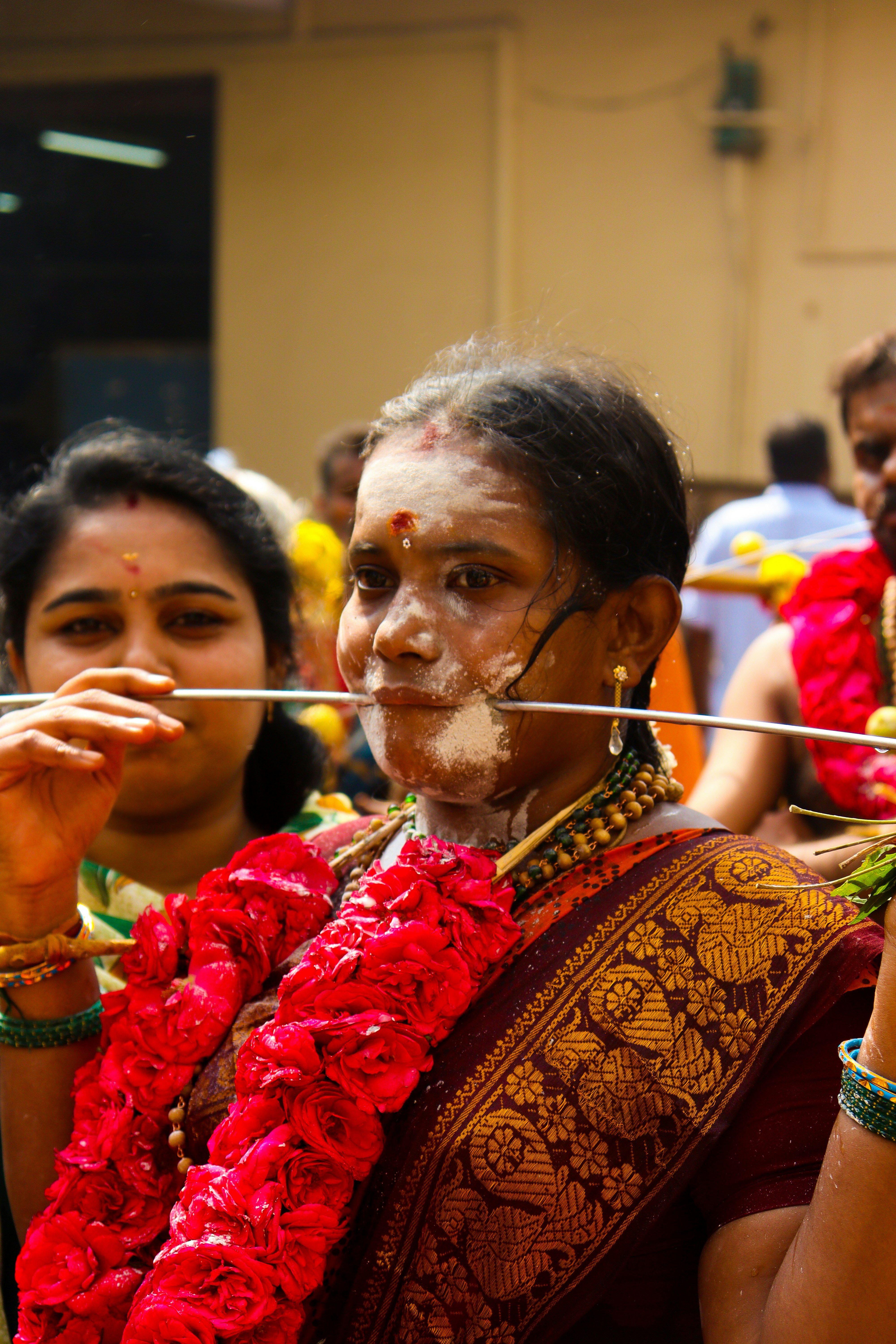 Festive ritual: a garlanded participant balances a ceremonial rod during a crowded celebration