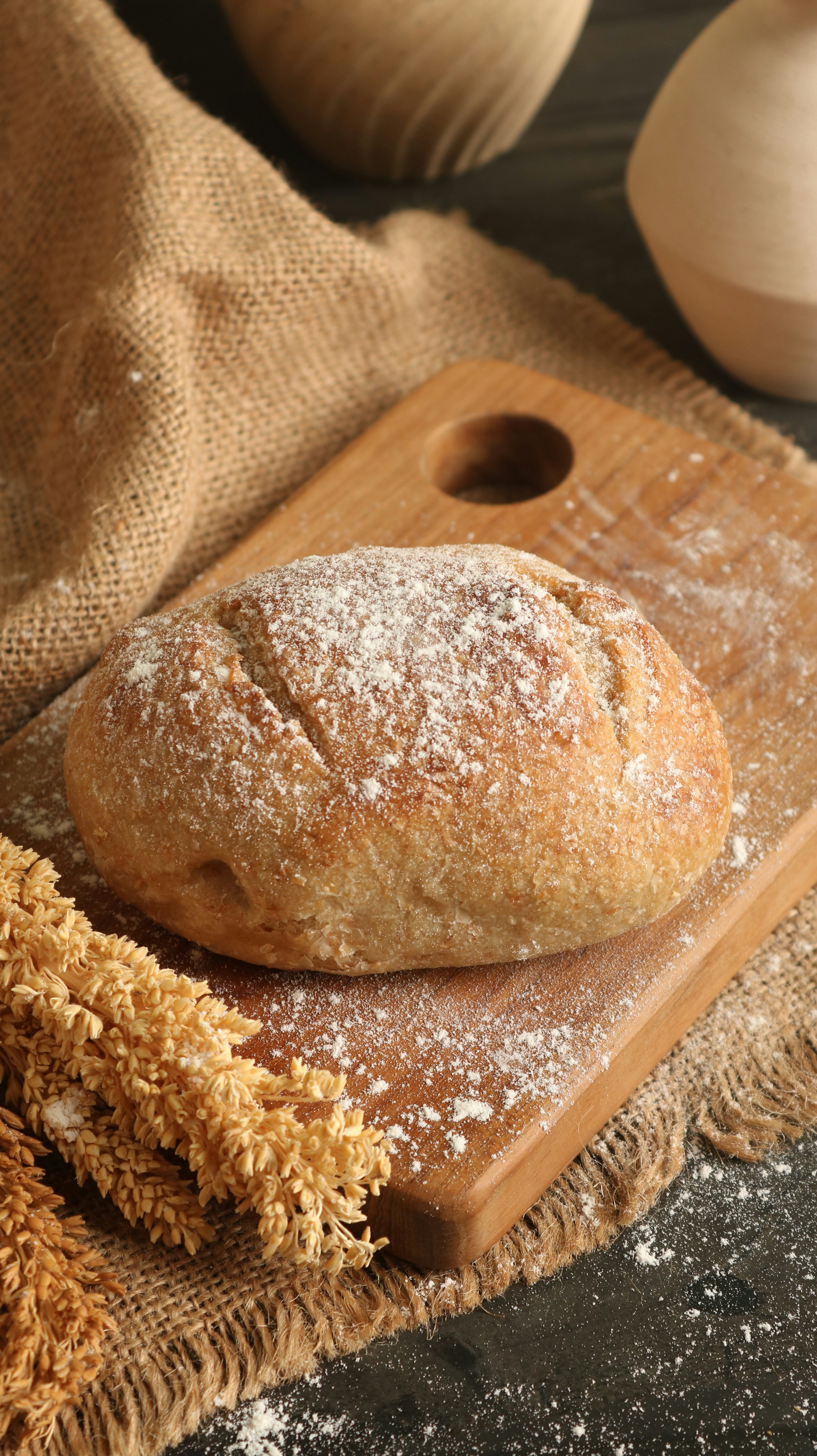 Dustings of Dawn: A Rustic Wheat Roll Resting on a Wooden Board