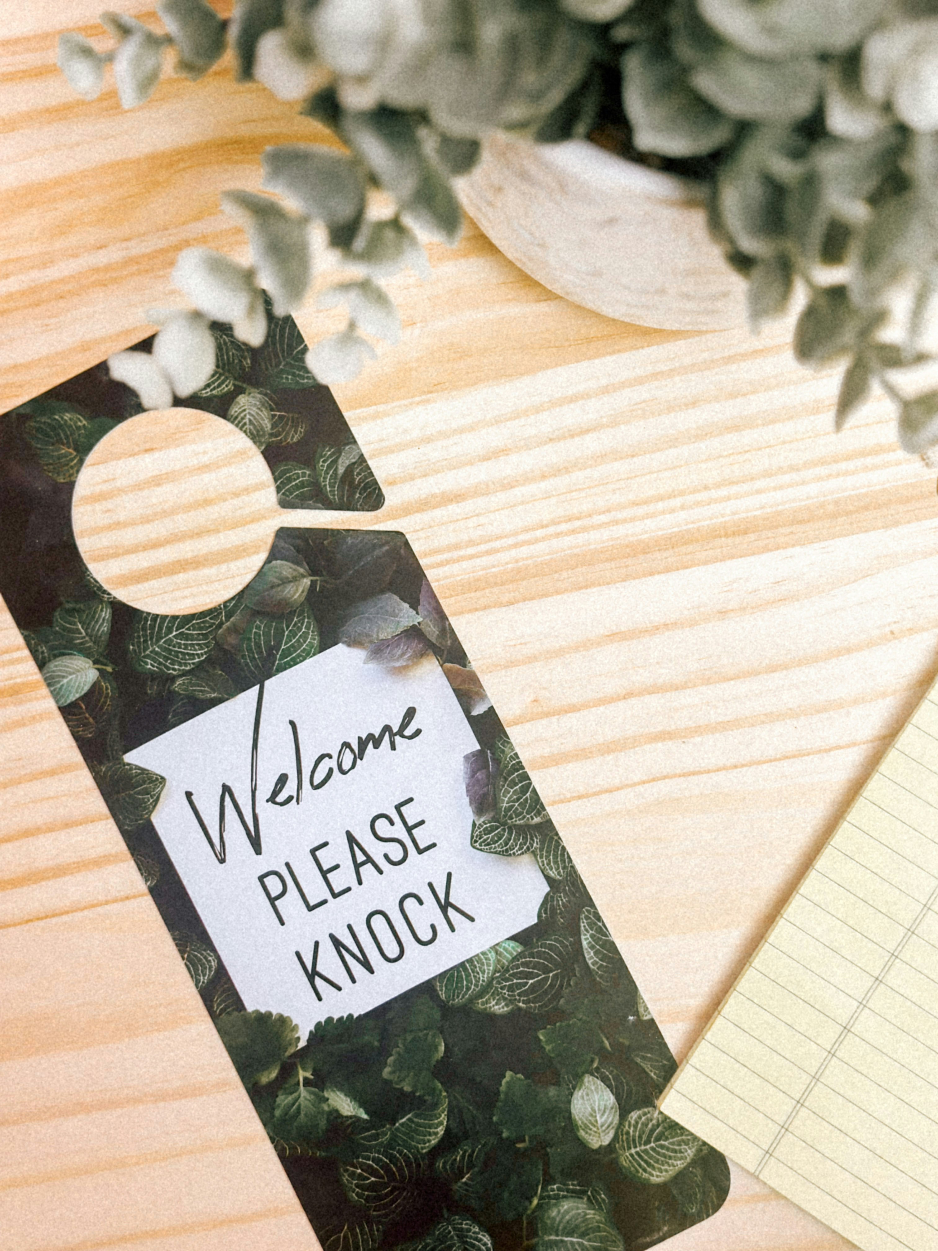 Welcome Sign Tag Peek: A Leafy Gatekeeper at the Door