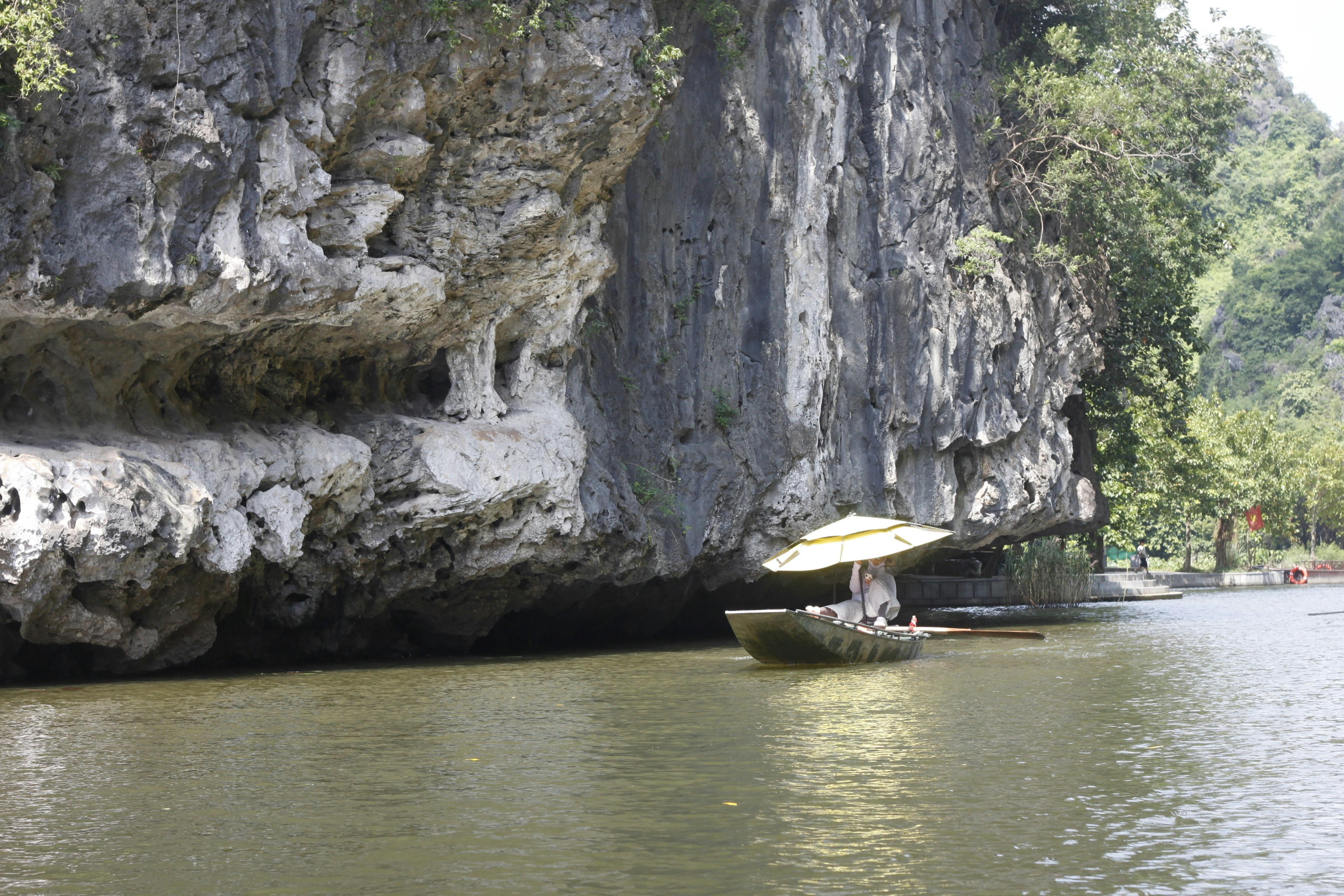 Sunlit Boat Under a Cliff: Quiet River Awakening