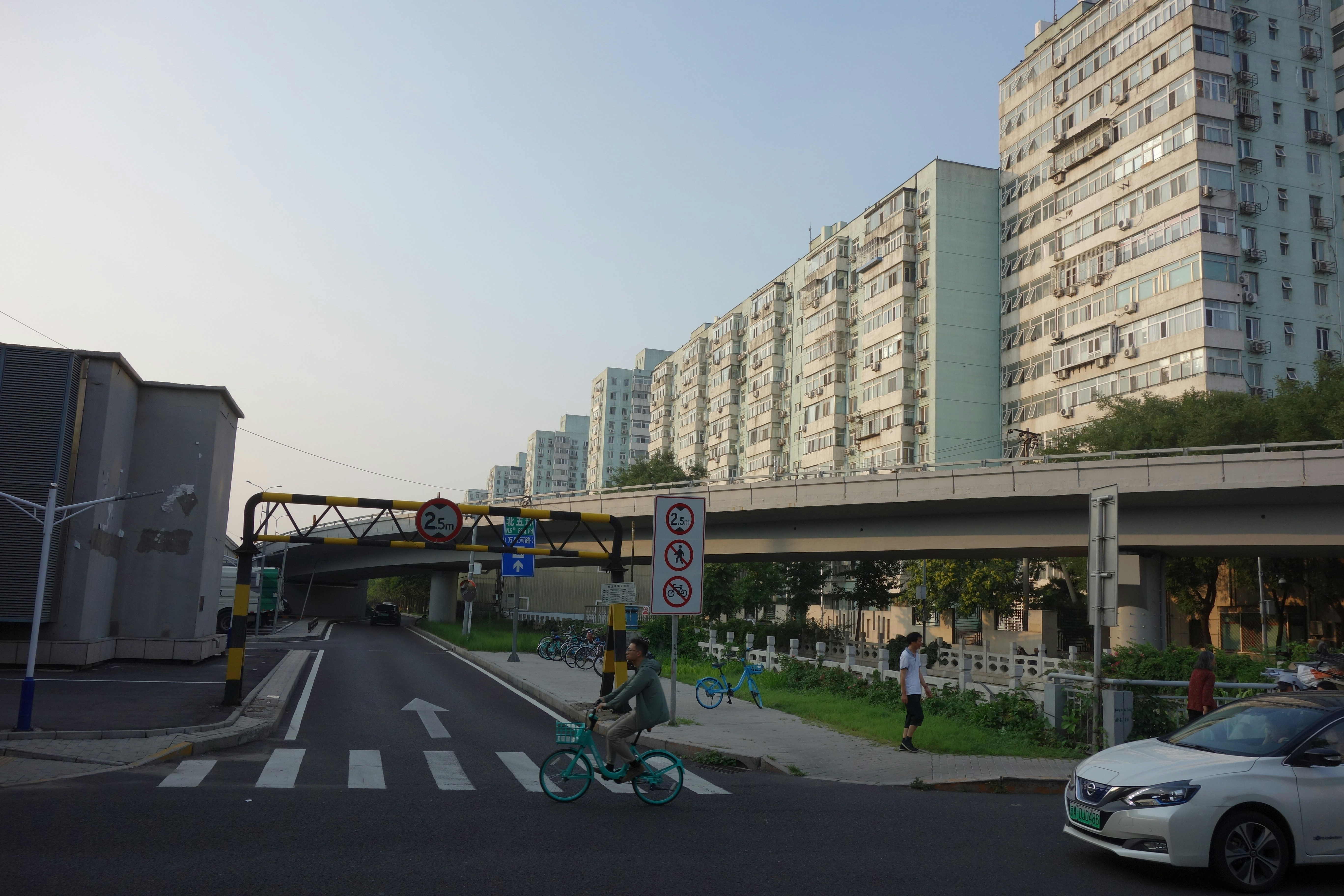 Urban Corridor: Cyclist at the Crossing Beneath a Row of Apartment Blocks