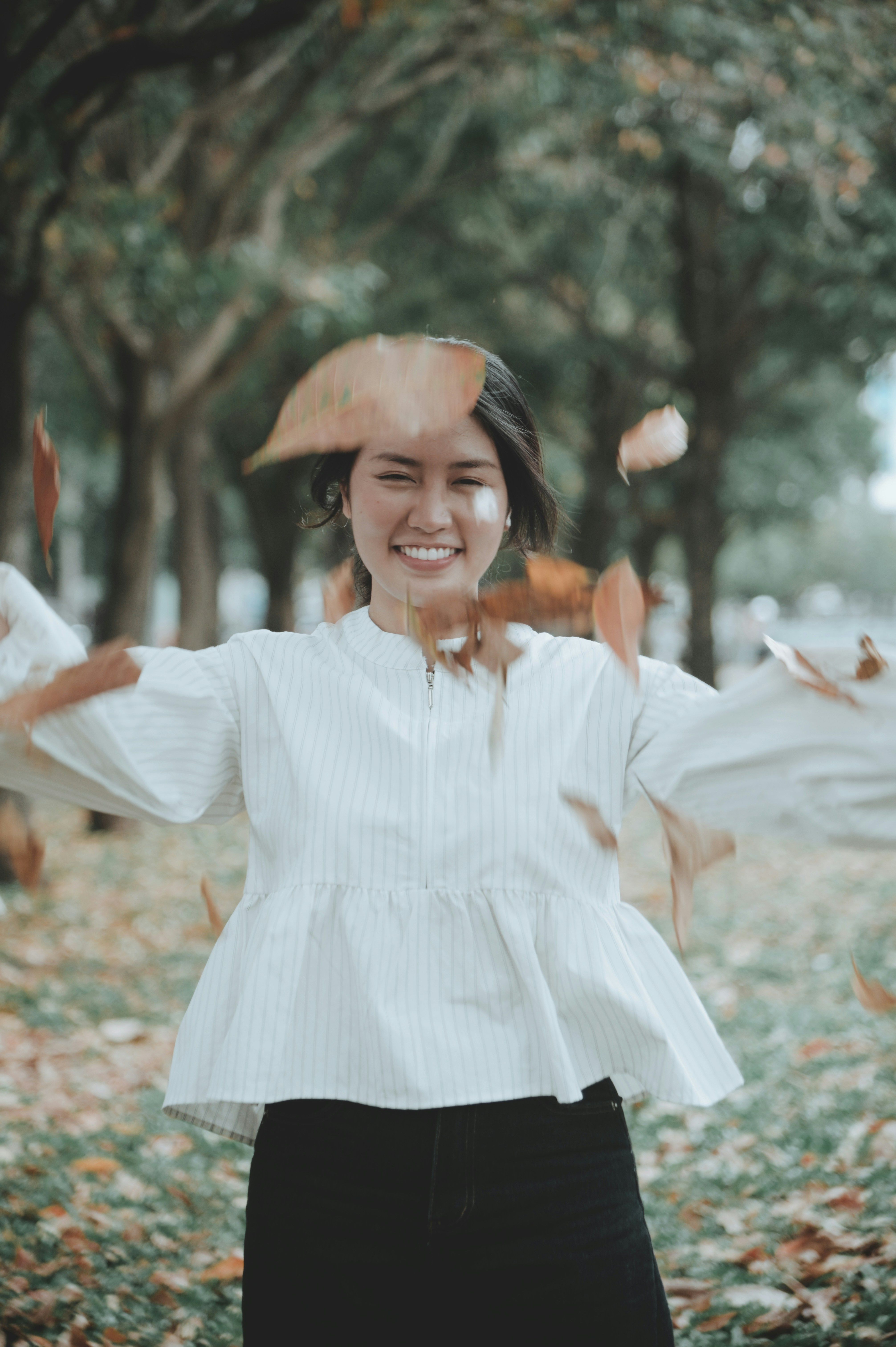 Autumn Breeze: A Smile Unfolds Amid Falling Leaves