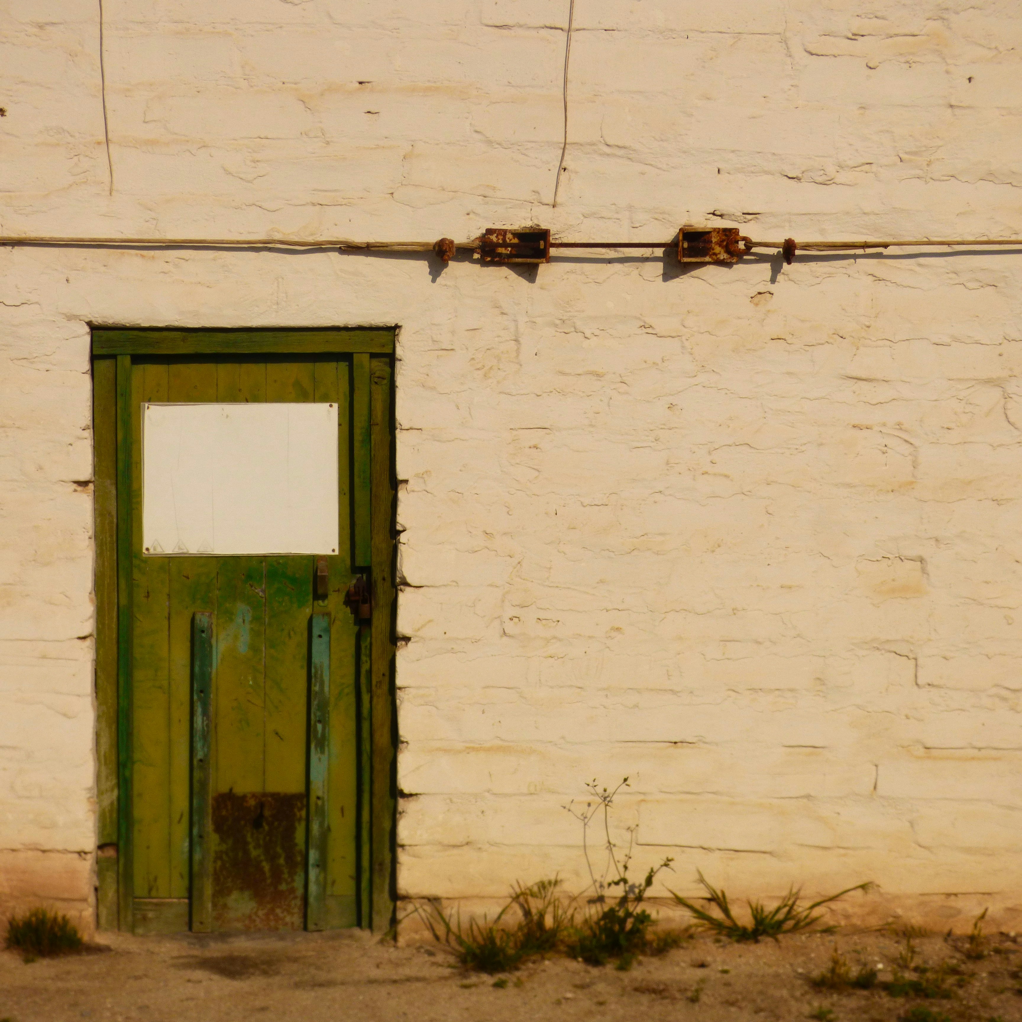 Weathered Green Door on Sunlit Adobe Wall