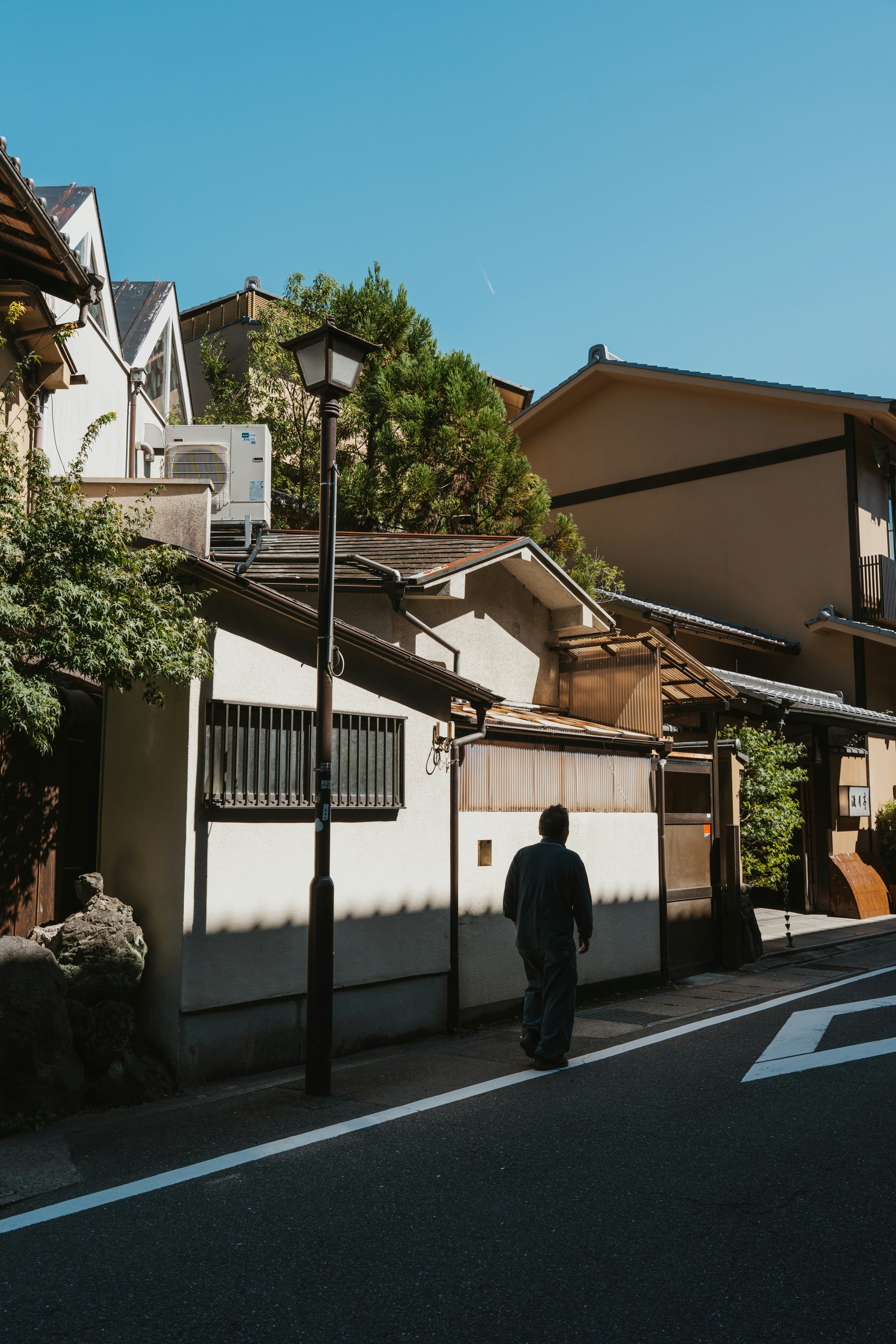Quiet street at dusk: a lone pedestrian beneath traditional architecture