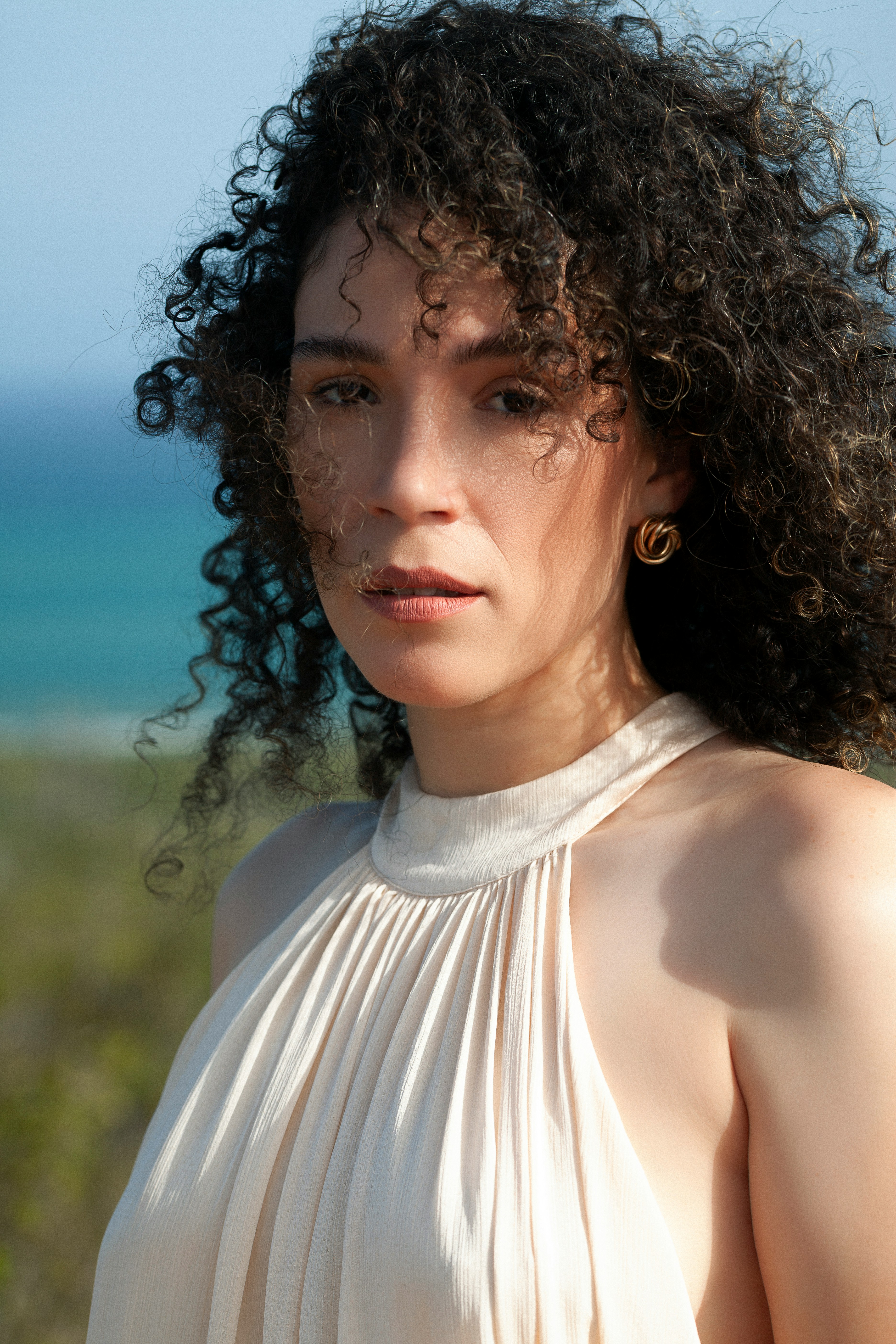 Sunlit Portrait on the Coast: Curly Hair Backlit by Sea Breeze